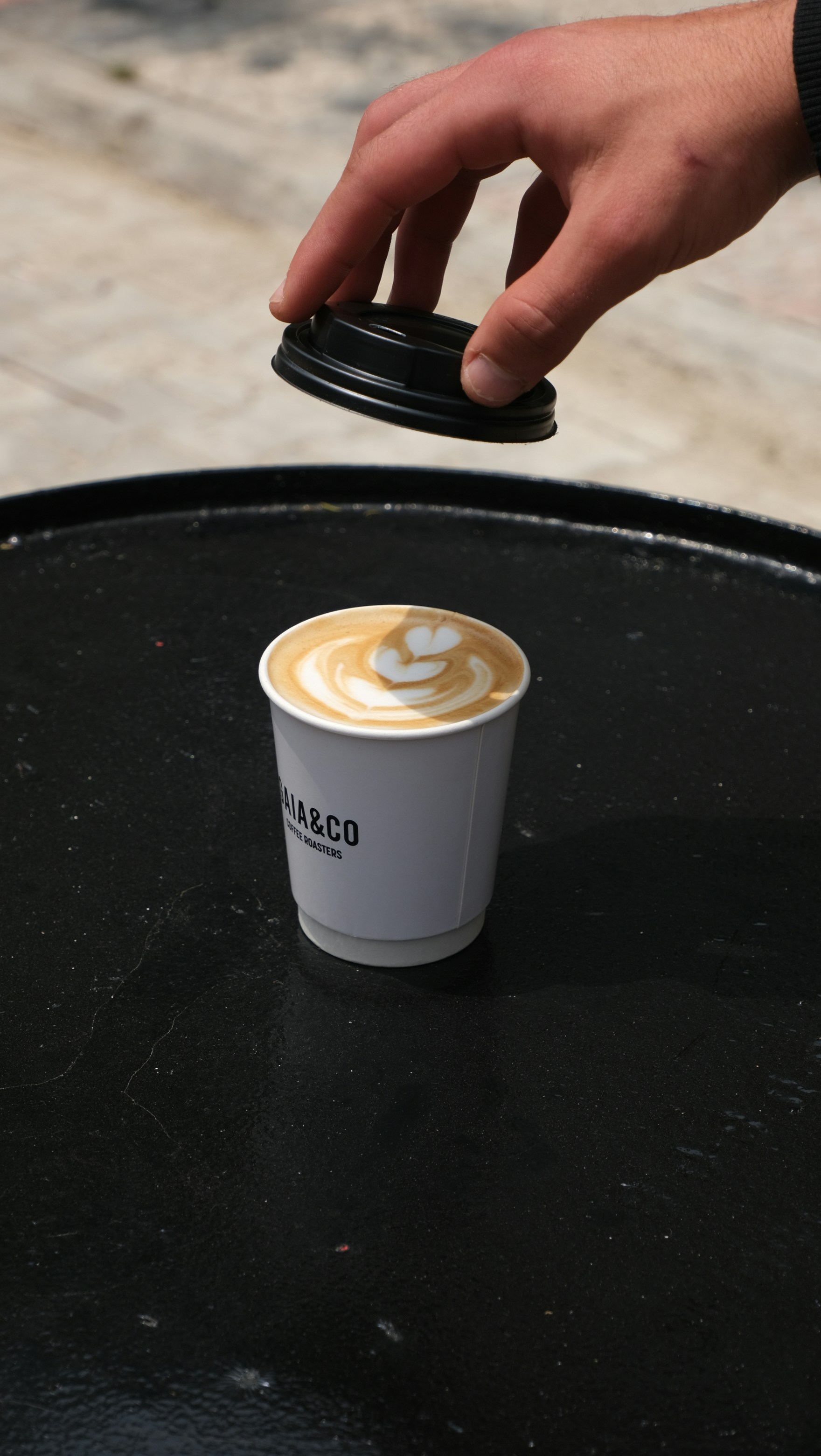 Latte Heart Unveiled: A Hand Lifts the Lid on a Dark Table