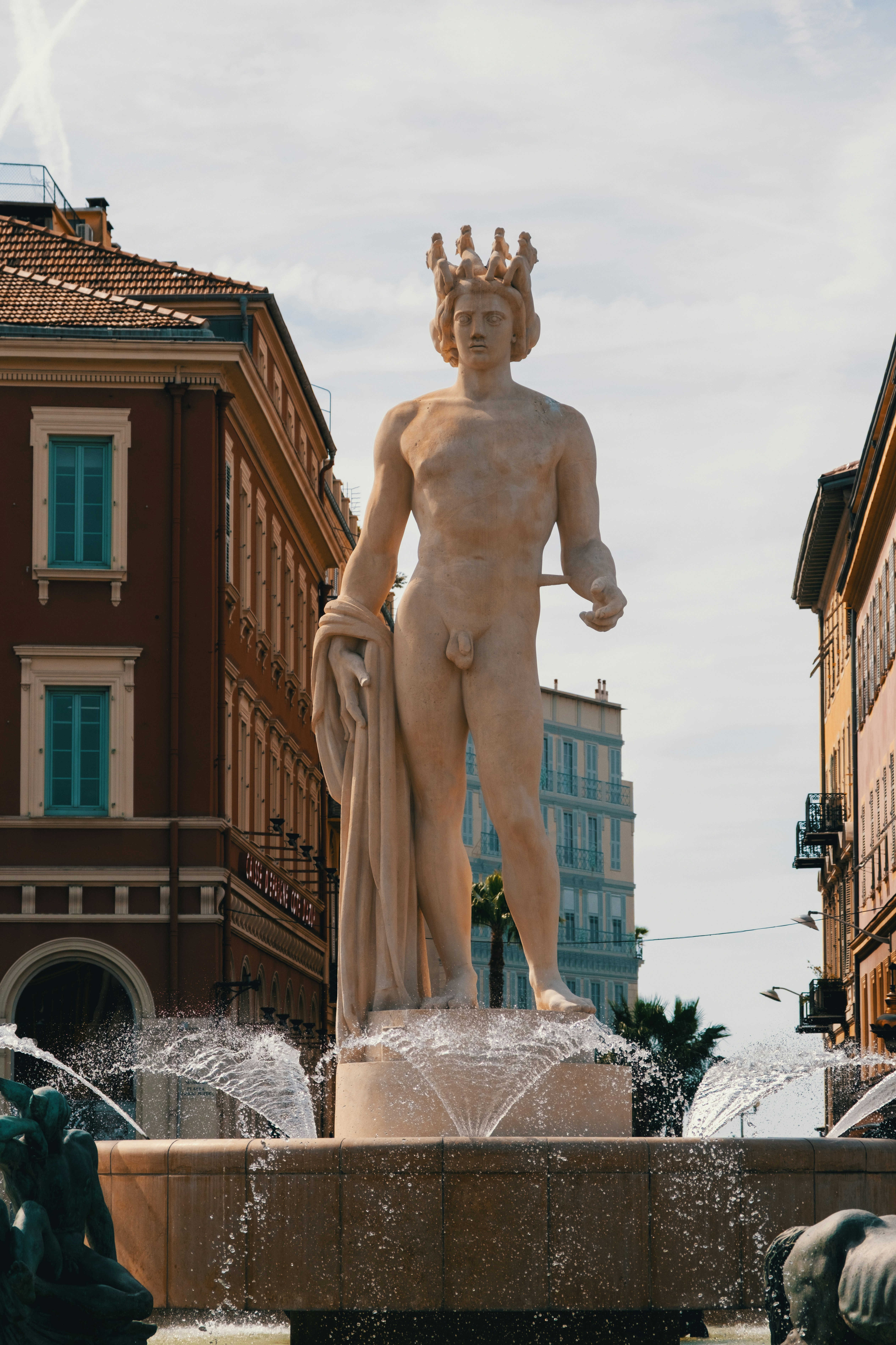 A statue of apollo stands in front of buildings. photo – Free Woman ...