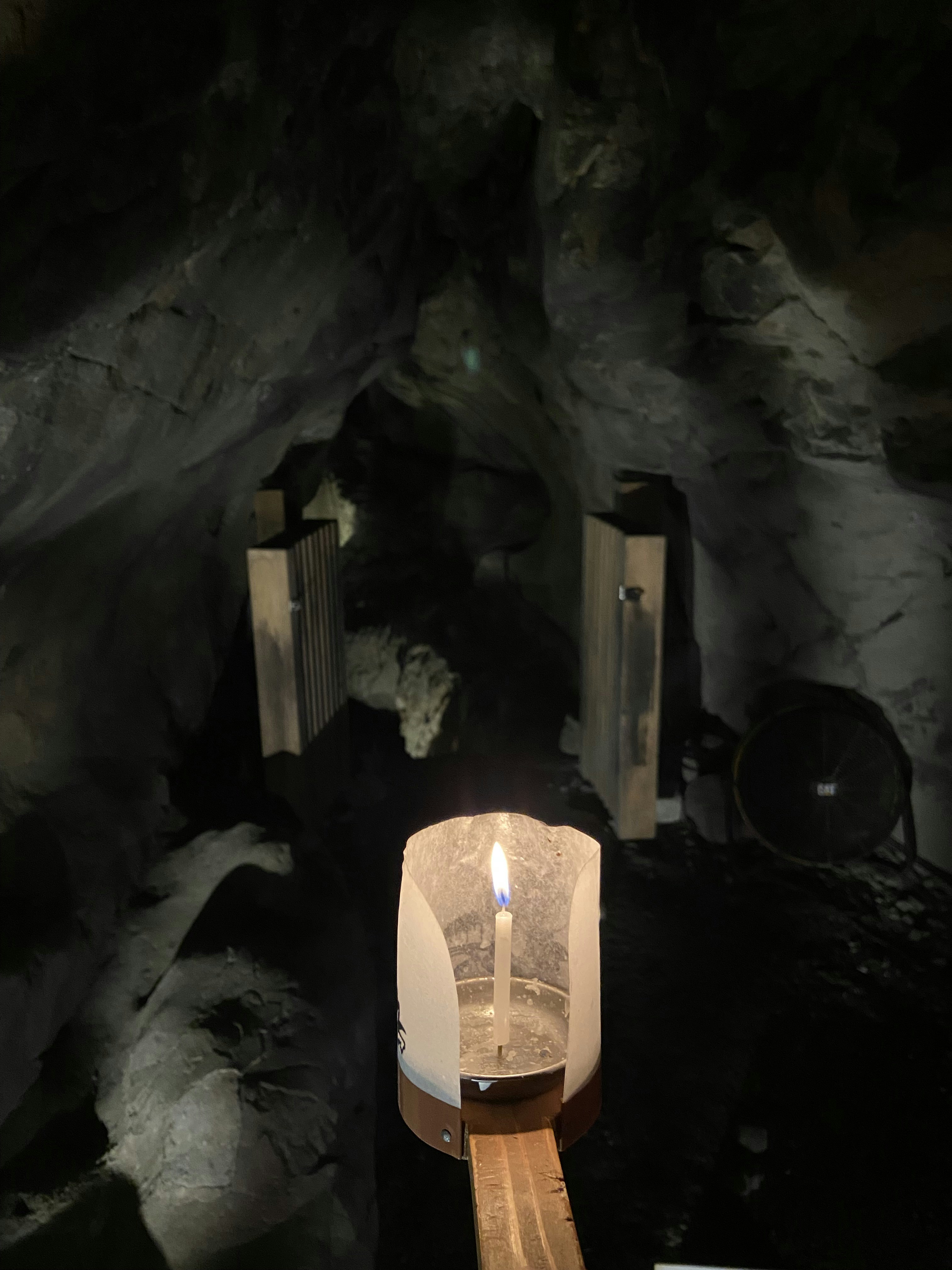 Flame at the Threshold: a lone candle guides through a shadowed cave