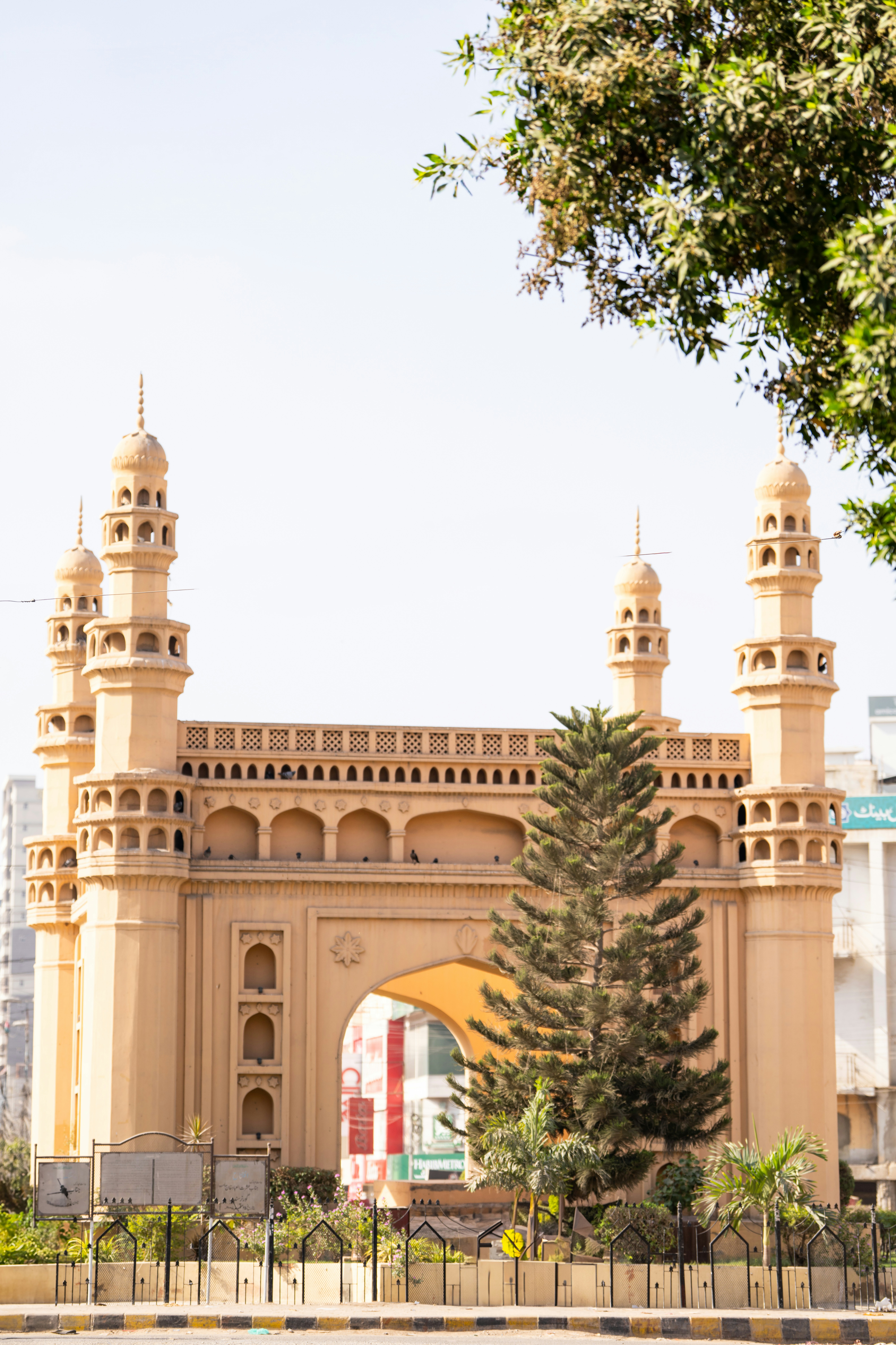 Historic Gateway Architecture in Karachi, Pakistan A vertical photograph of a historic gateway-style architectural landmark in Karachi, Pakistan. The structure showcases traditional design elements with minarets and arches, bathed in warm sunlight. Framed with greenery and urban surroundings, the image reflects a blend of cultural heritage and city life. Suitable for themes related to architecture, South Asian landmarks, travel, and historical tourism. | The charminar is an iconic monument in india.