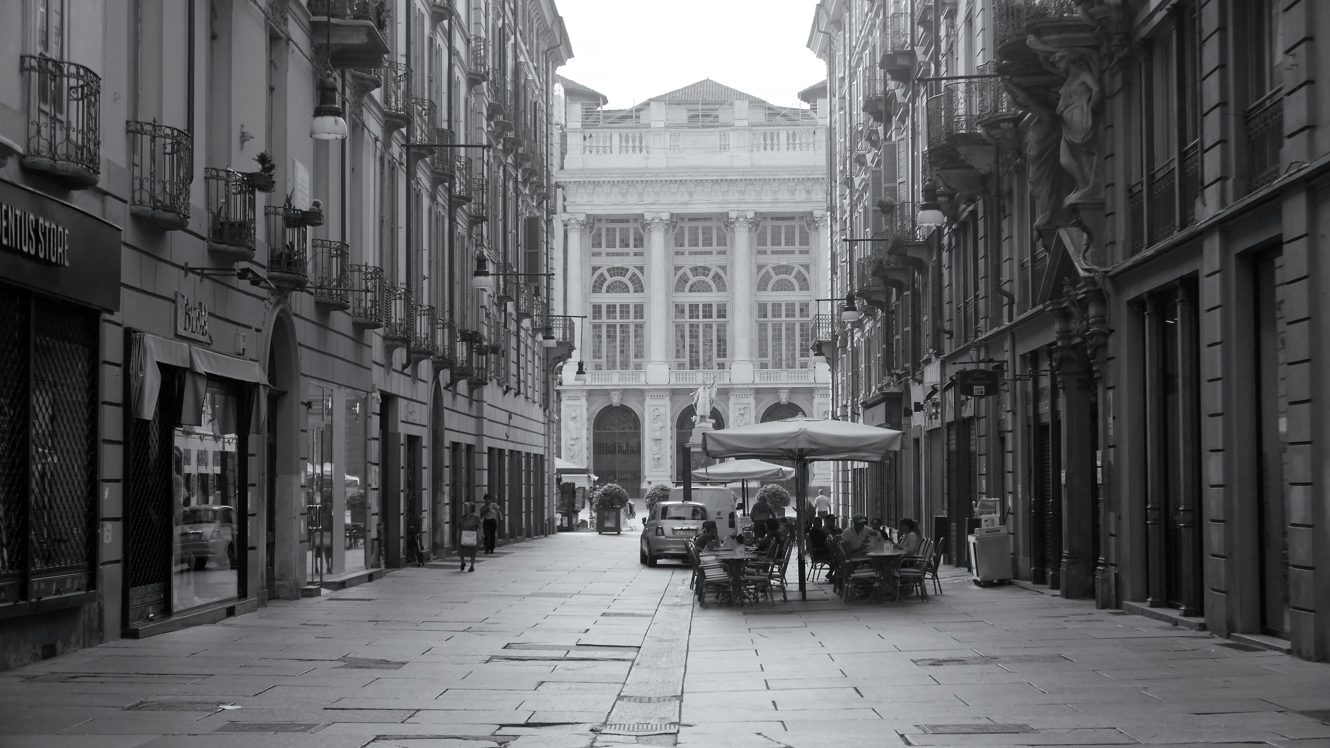 A serene urban street scene featuring a café and elegant architecture, captured in monochrome tones.