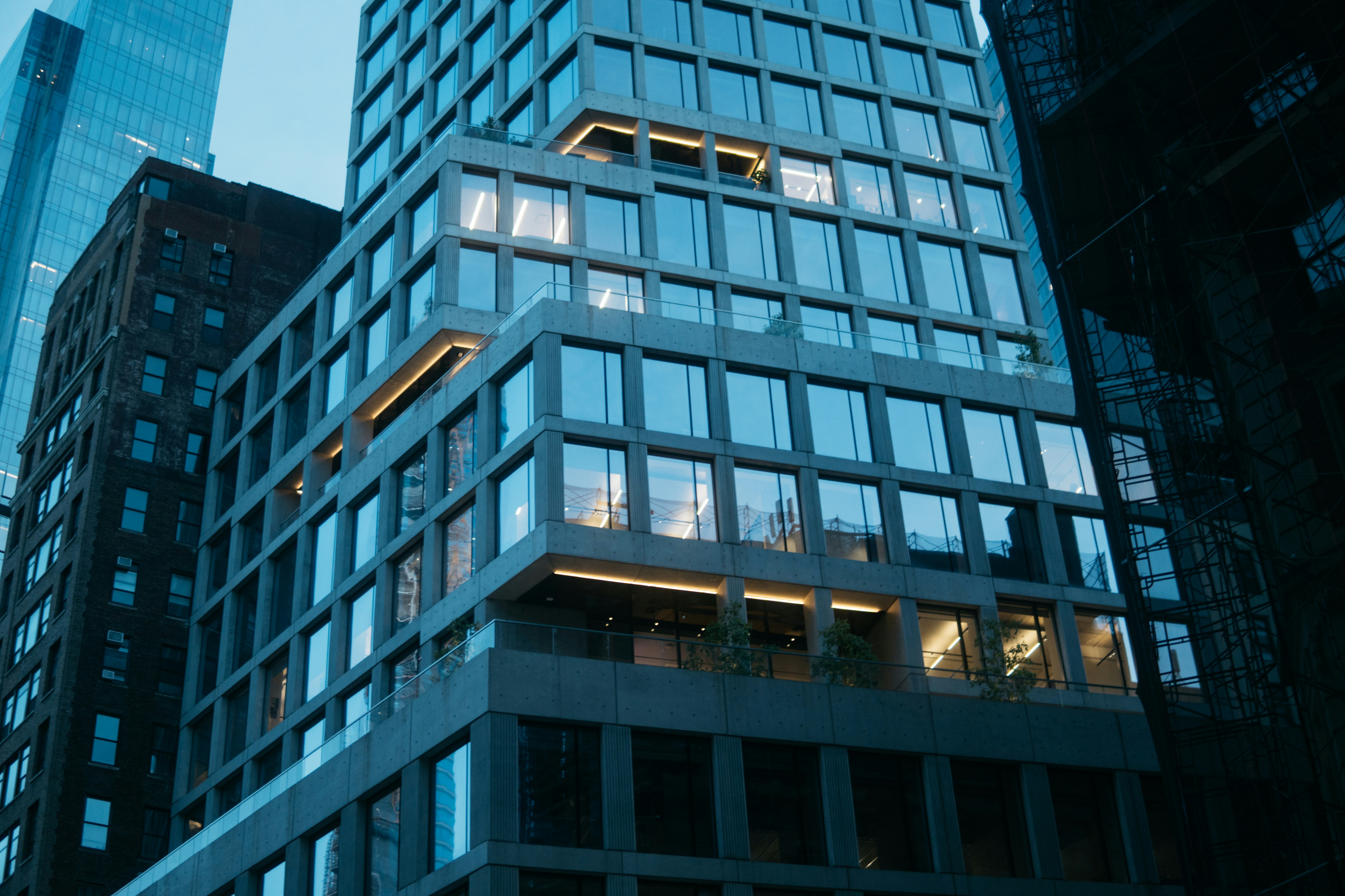 A modern skyscraper stands amidst other buildings.