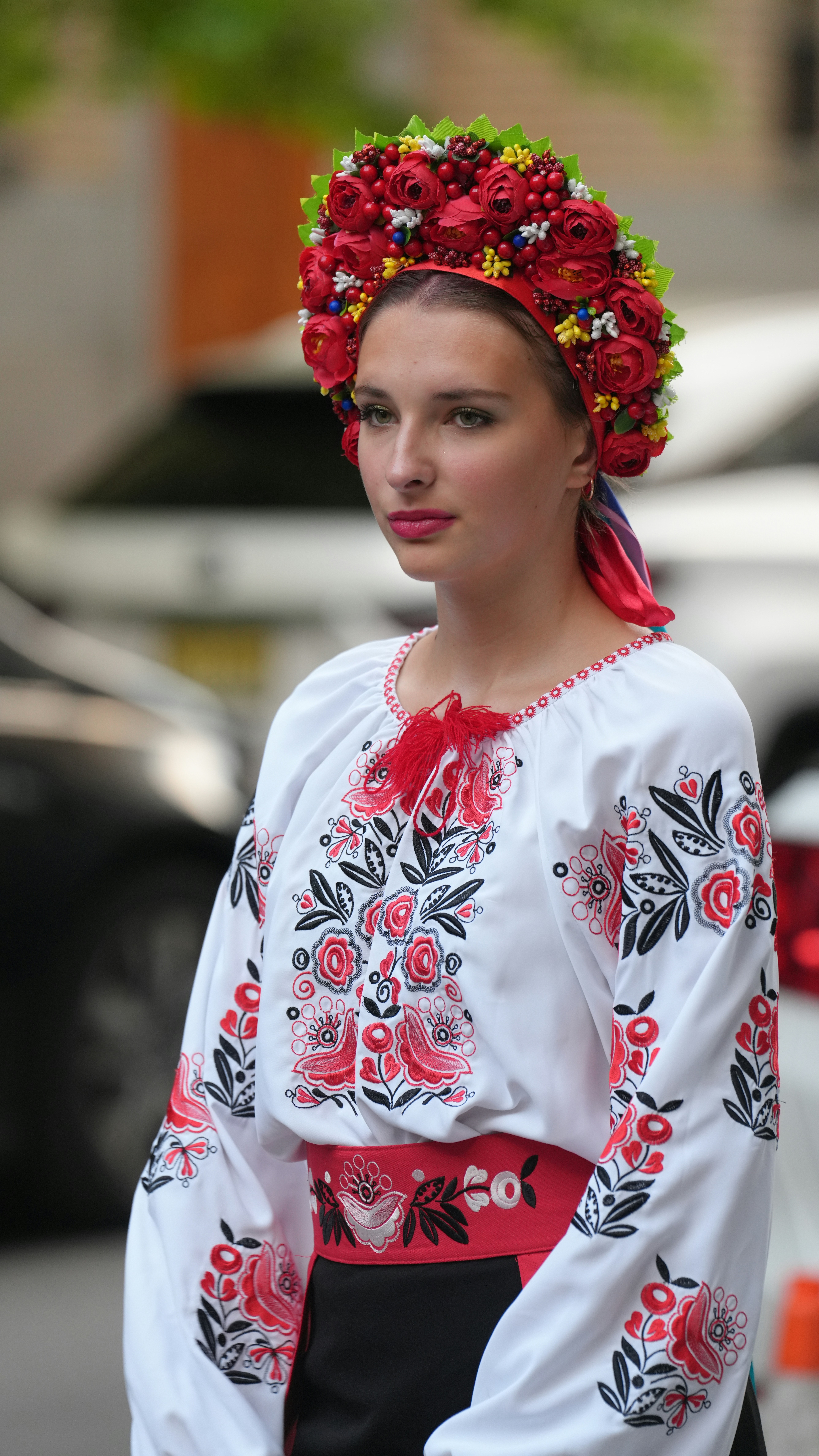 Young woman adorned in traditional attire with floral headpiece, showcasing cultural heritage during a vibrant festival.