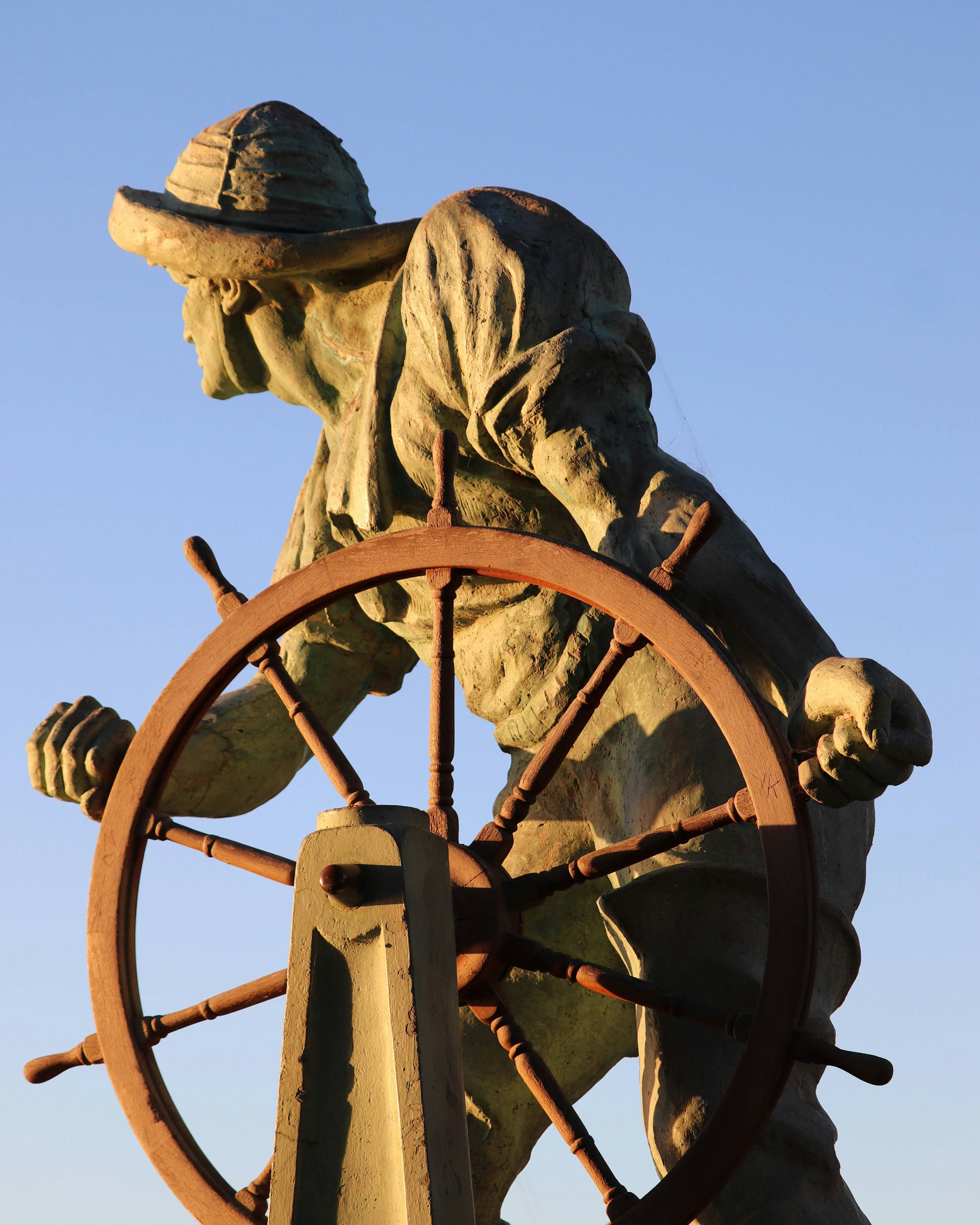 A statue depicts a sailor gripping the ship's wheel. photo – Free Art ...