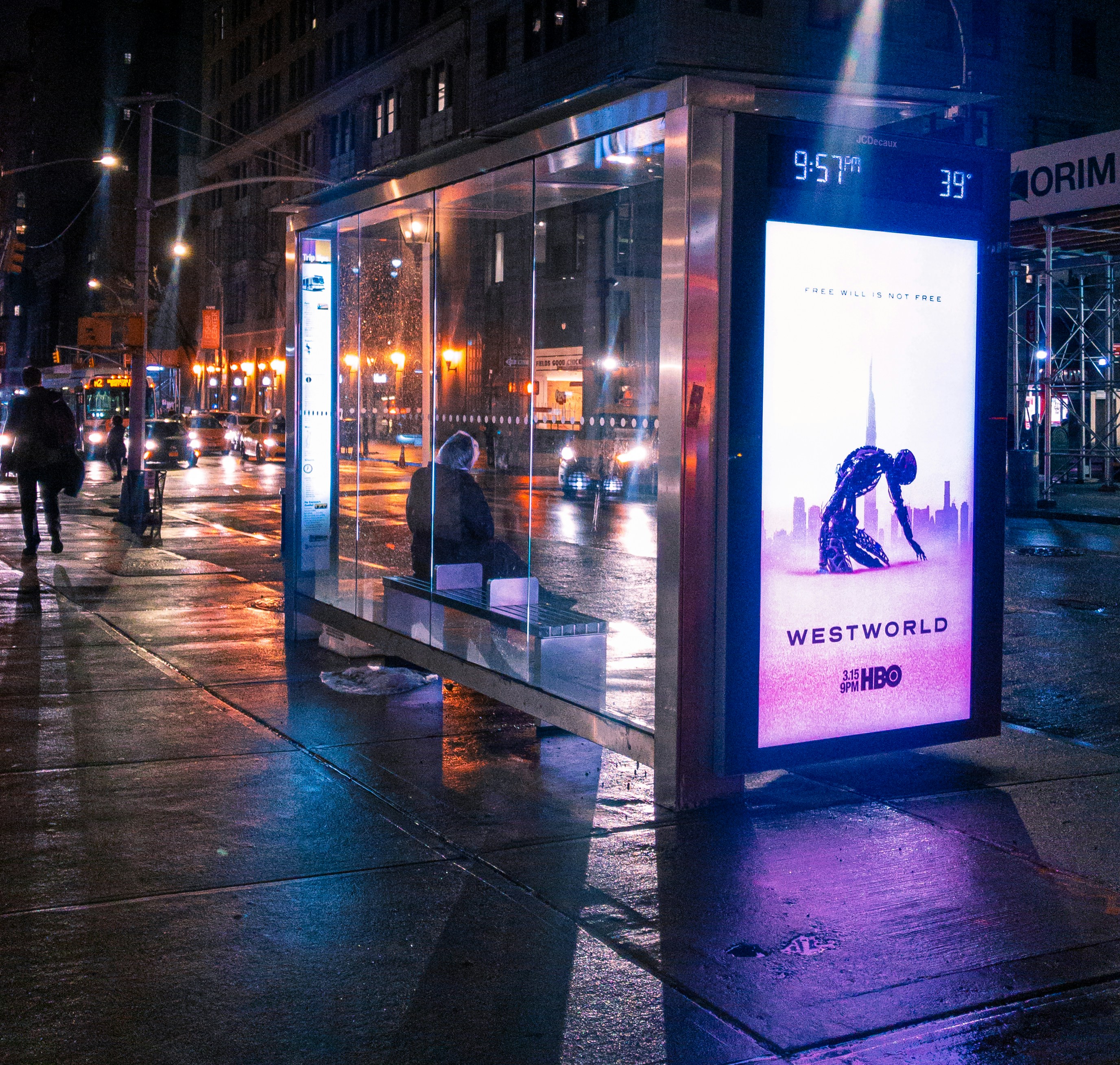 A person waits at a bus stop with a westworld advertisement. photo ...