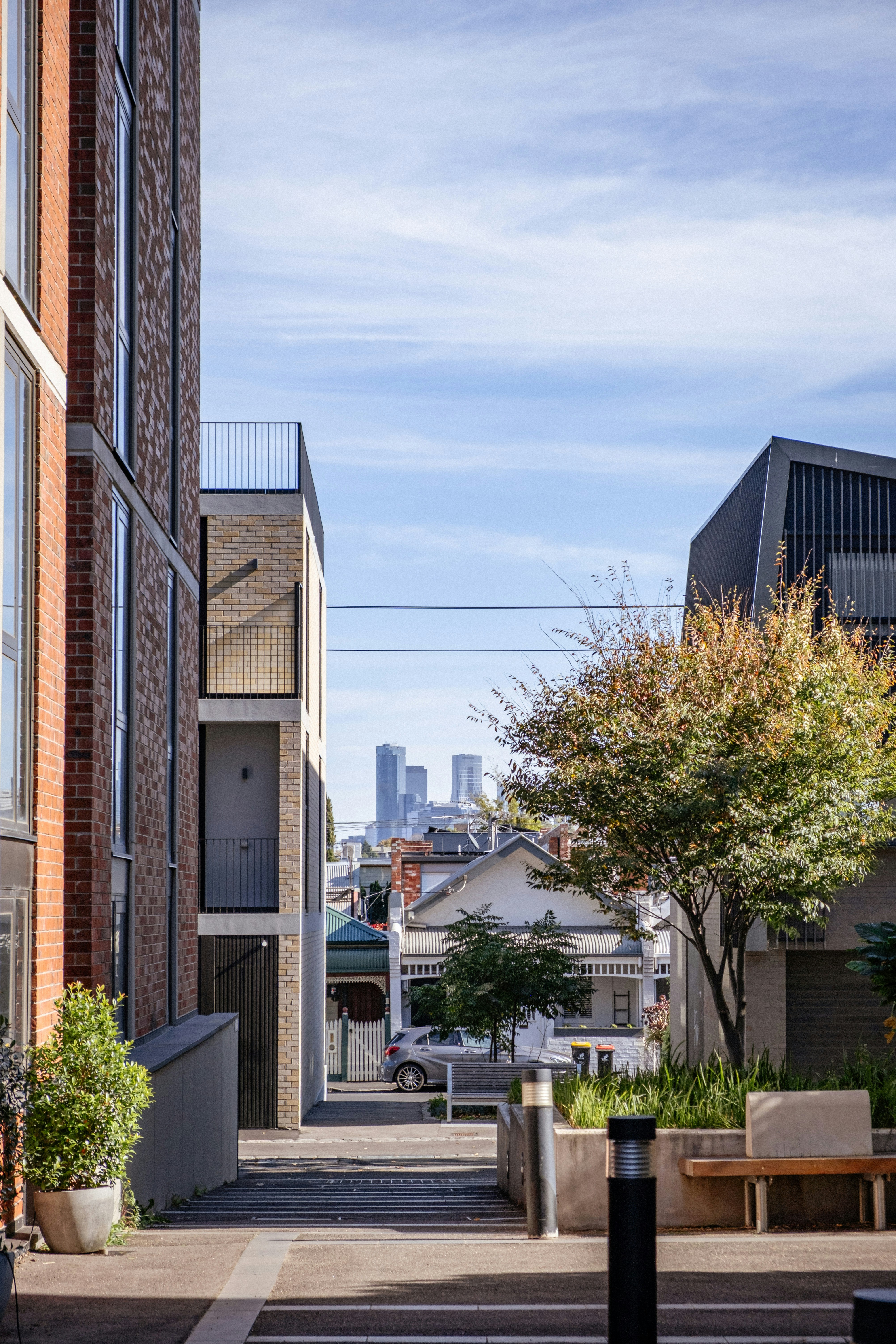 Modern architecture frames a serene pathway leading to a distant city skyline, showcasing a blend of urban living and nature.