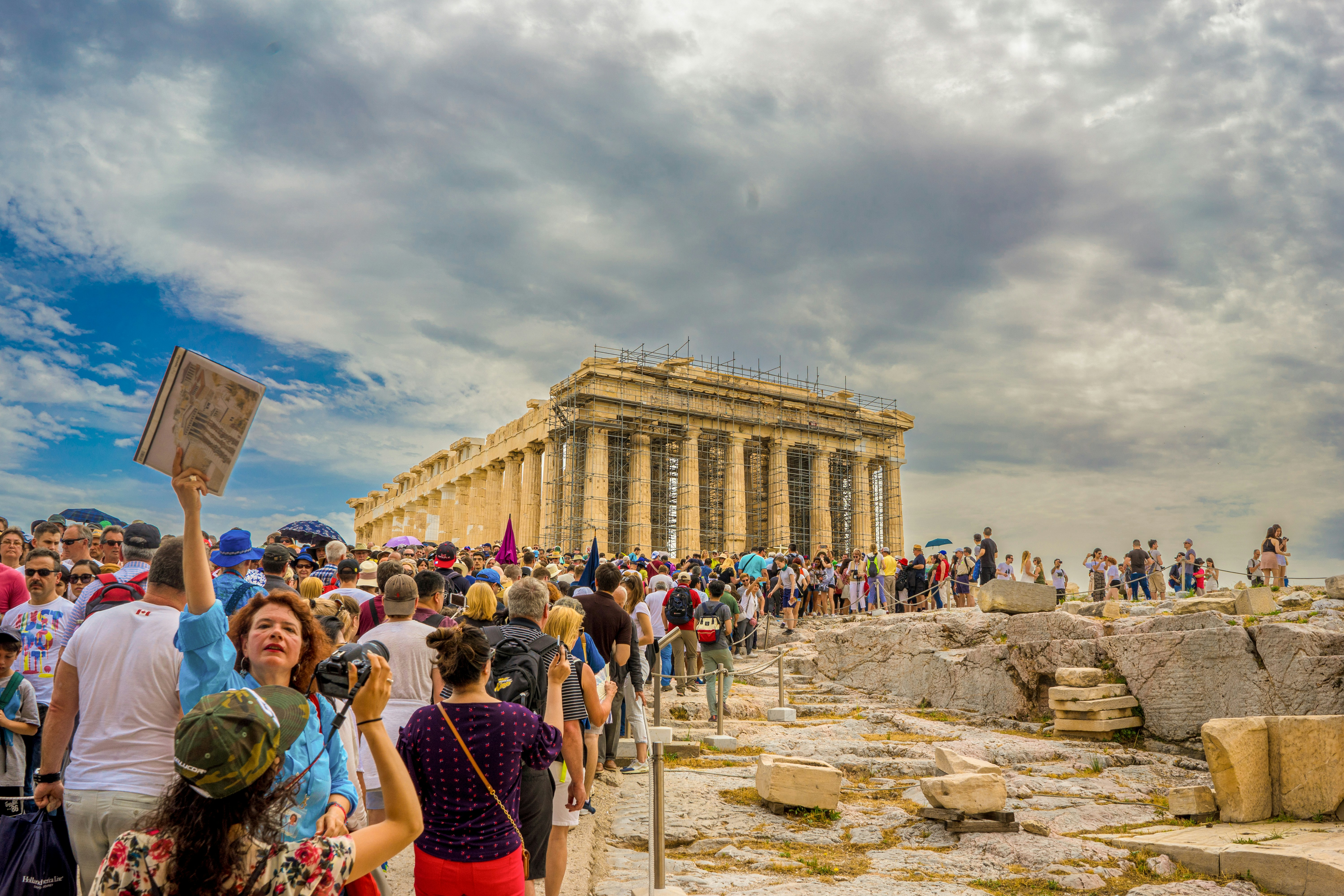March Toward the Parthenon: Crowds Thread the Acropolis Beneath Looming Clouds