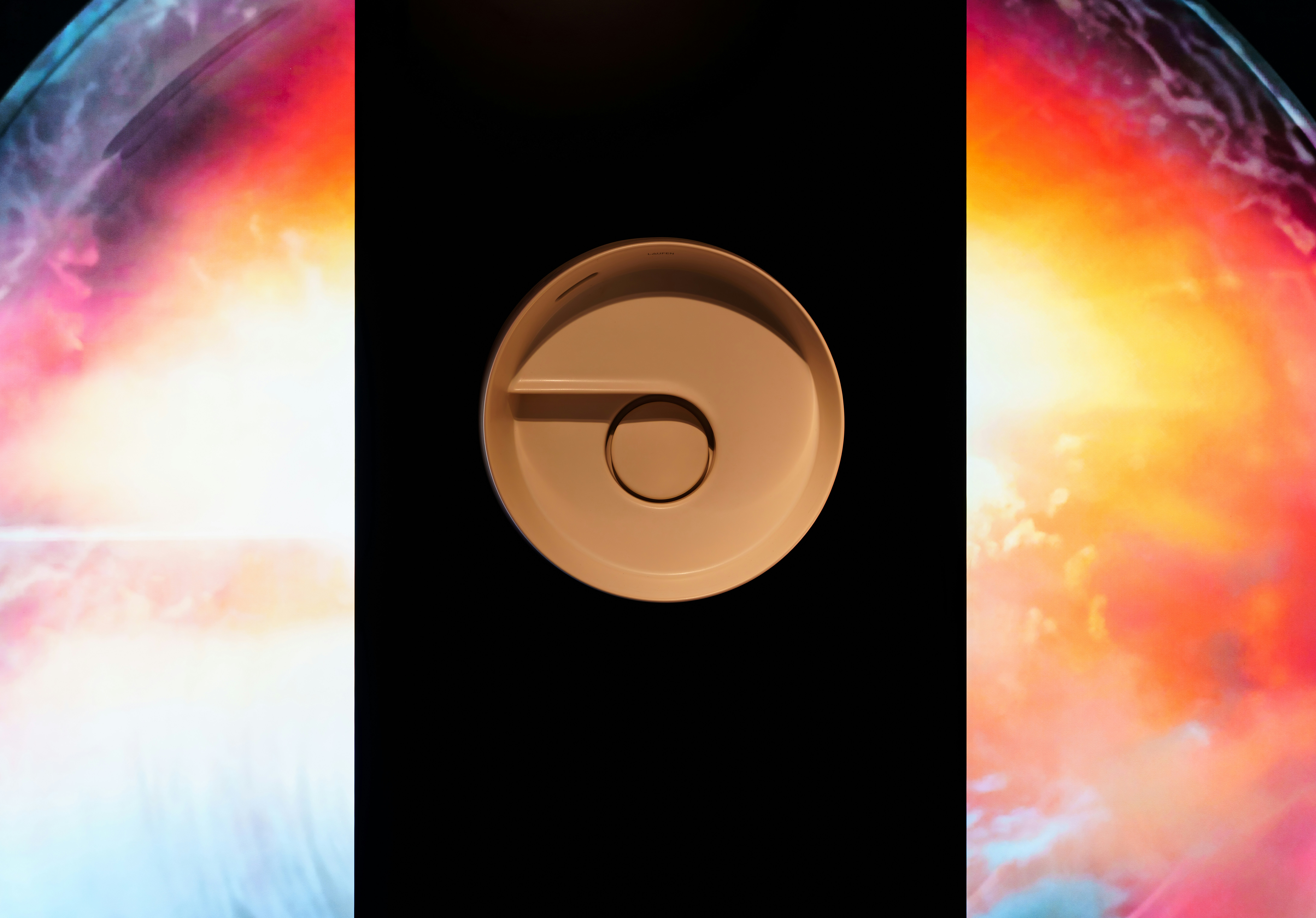 Minimalist design featuring a circular object with a unique cutout, surrounded by vibrant colors and abstract patterns. 