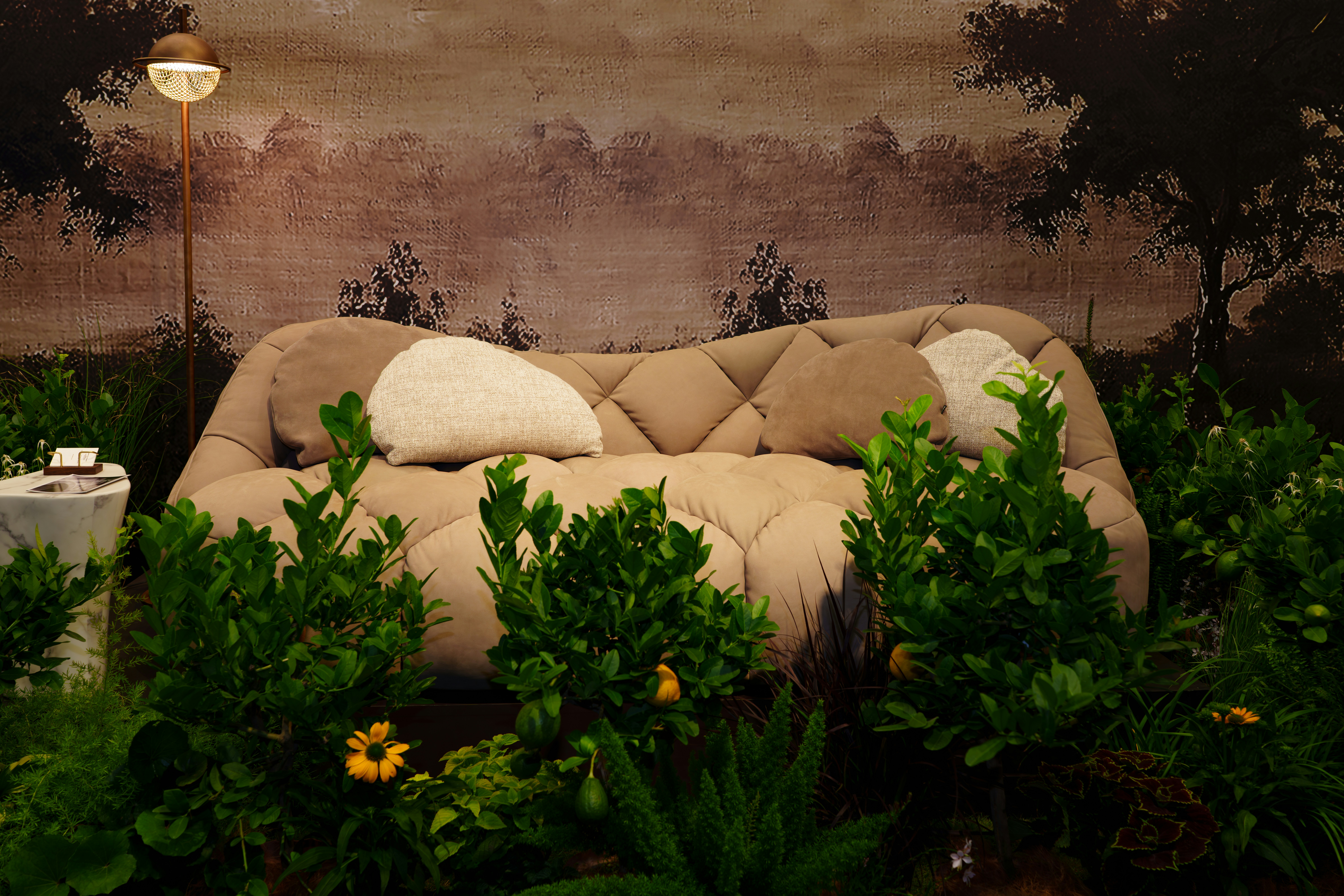 A plush sofa adorned with soft cushions nestled among lush greenery, set against a textured backdrop of trees and earth tones.