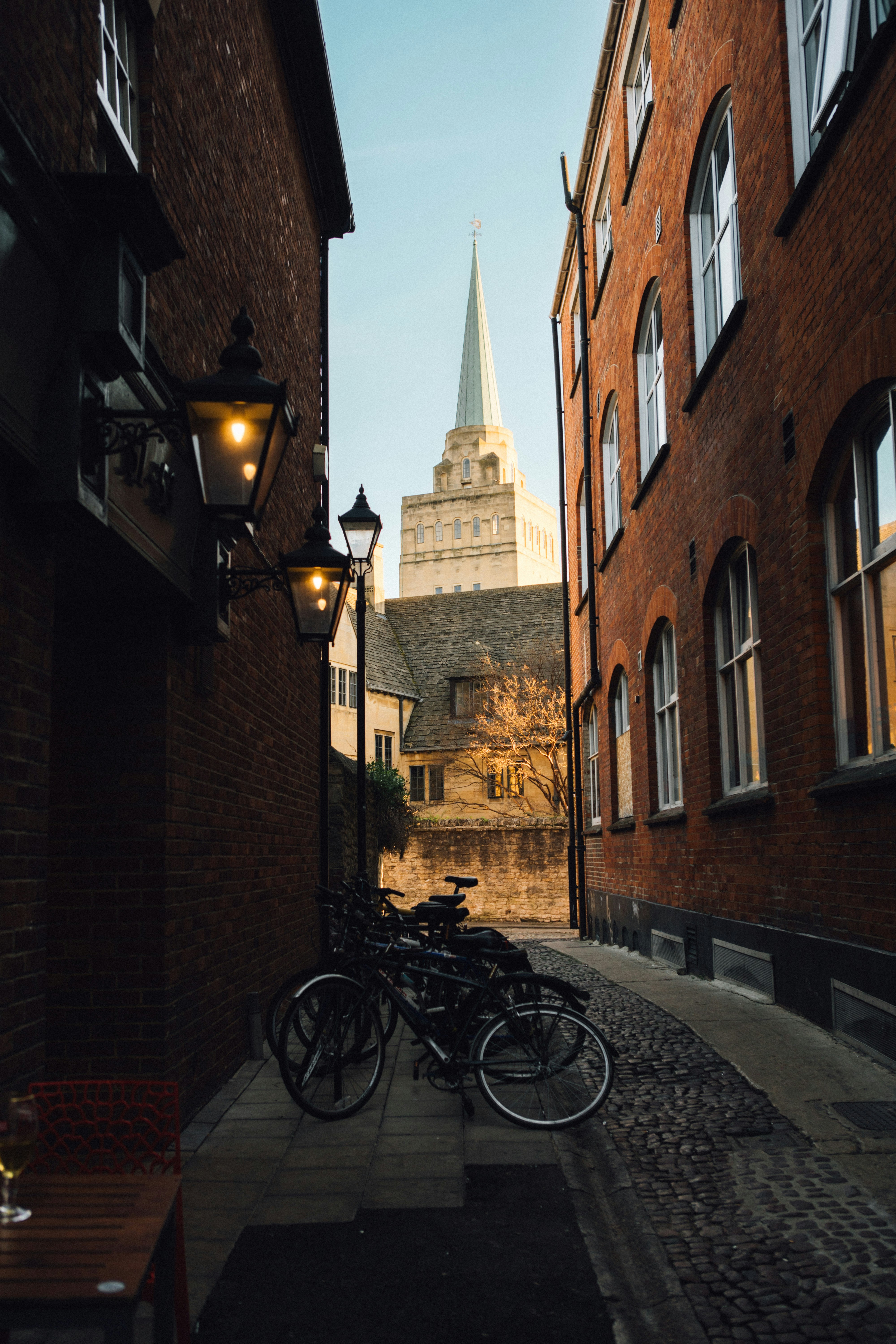 A narrow alleyway leads to a tall church spire.