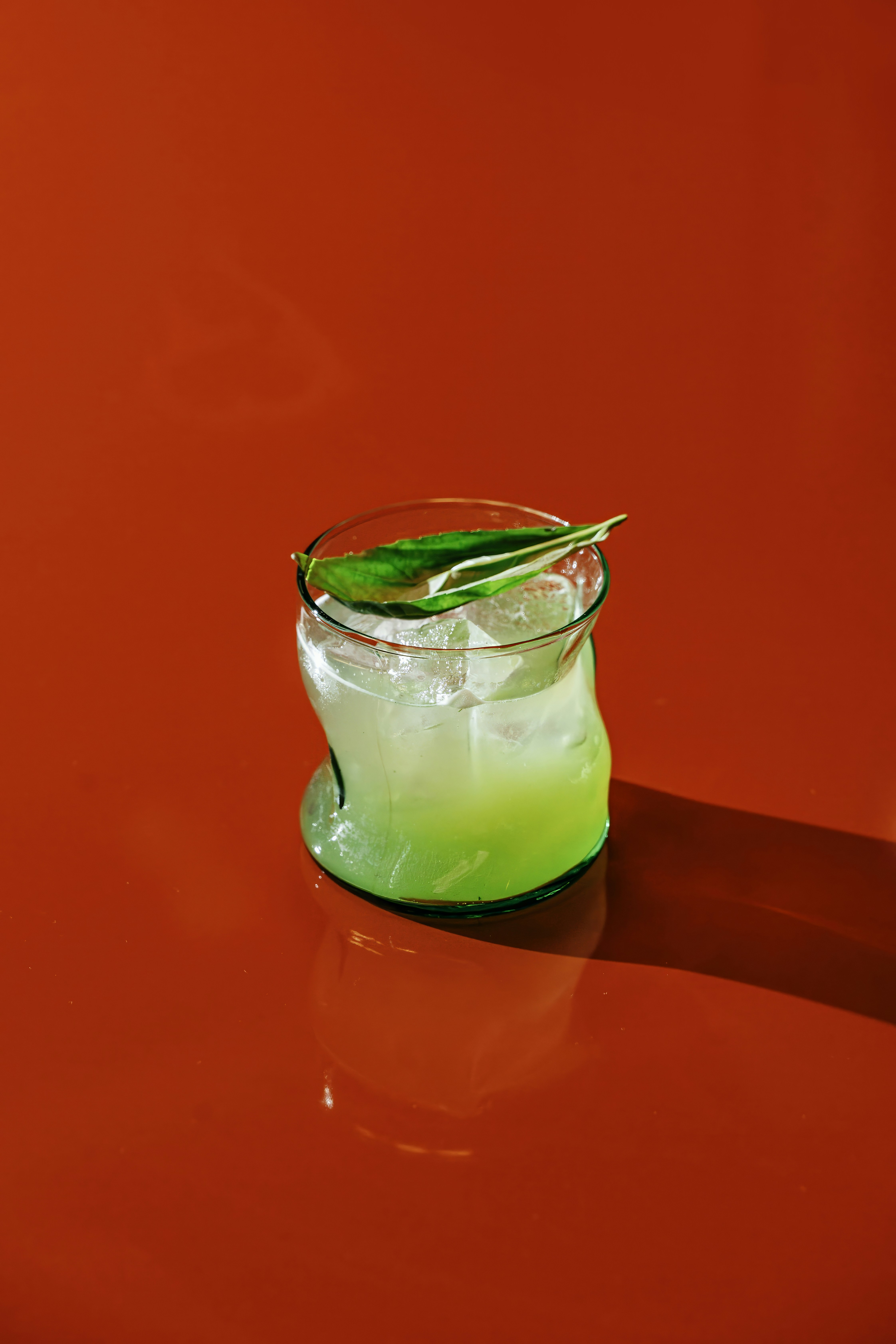 Citrus Glow: Green Cocktail on a Crimson Stage