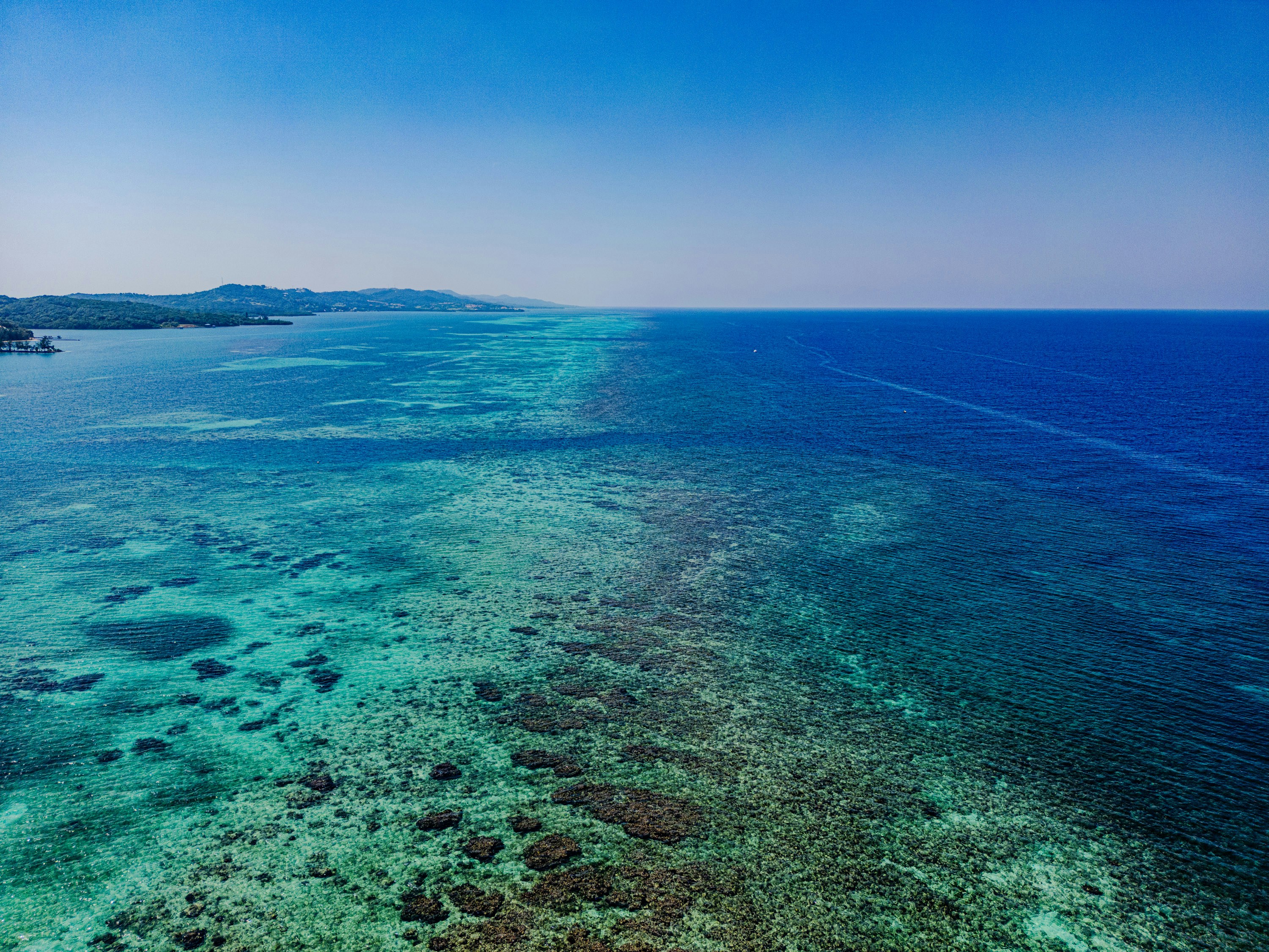 Mar abierto Roatán islas de la Bahía. Honduras. Fotografía profesional en Honduras para marcas y proyectos creativos. Portafolio: www.concepto1719.com Disponible para proyectos editoriales y comerciales. | Vibrant blue ocean and coral reef under sunny skies.
