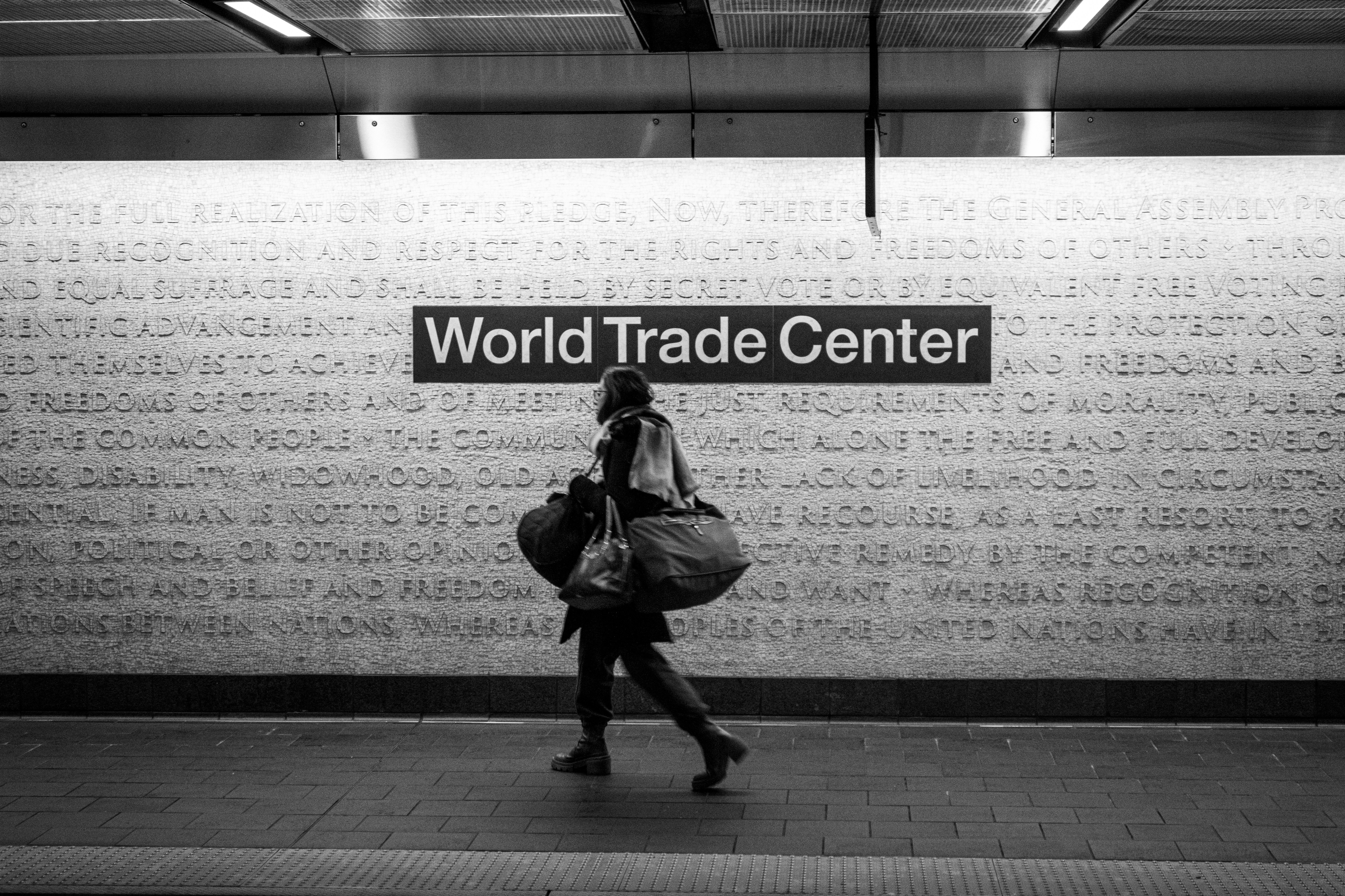 A person walks past the world trade center sign. photo – Free City ...
