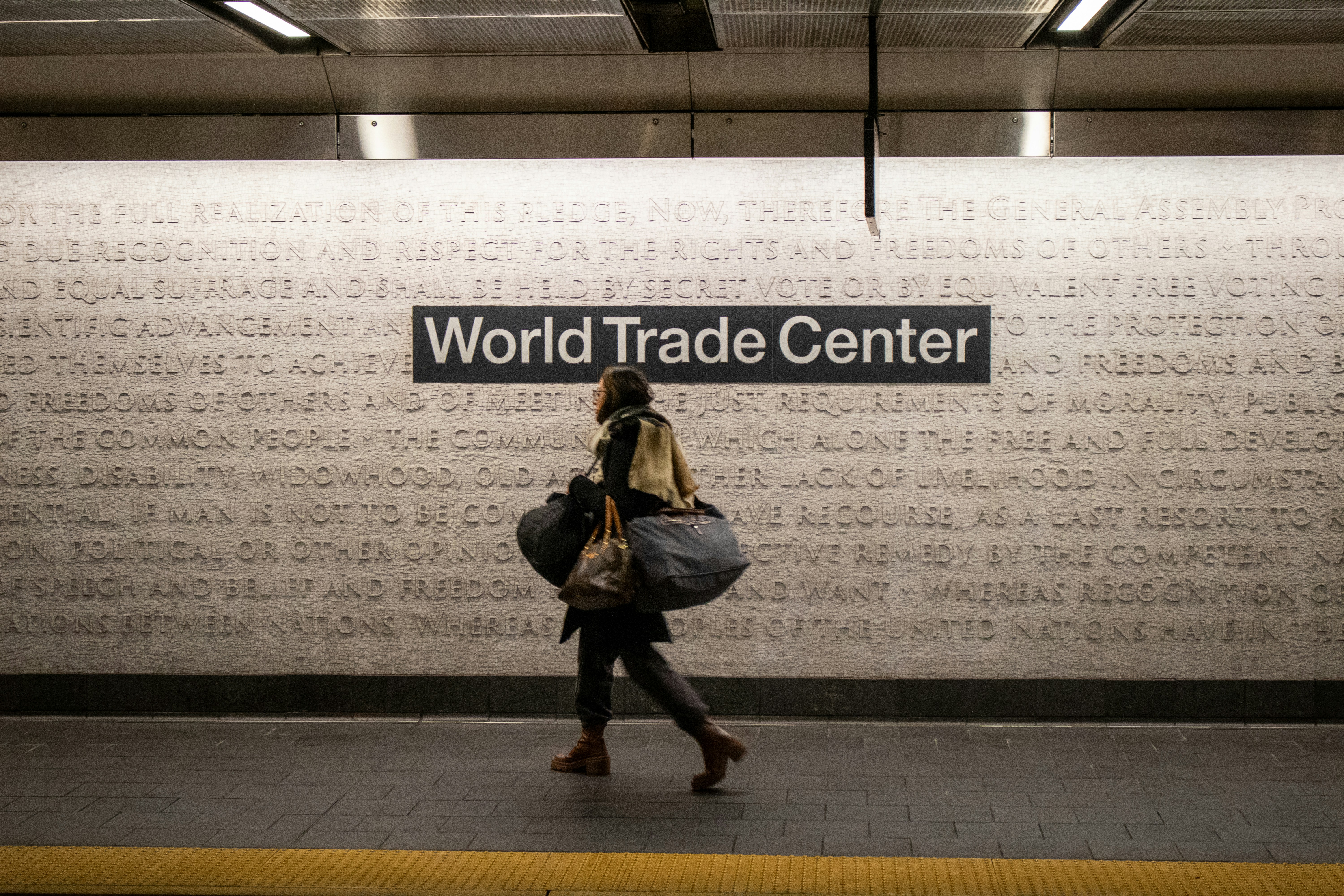 A person walks past a world trade center sign. photo – Free City Image on Unsplash