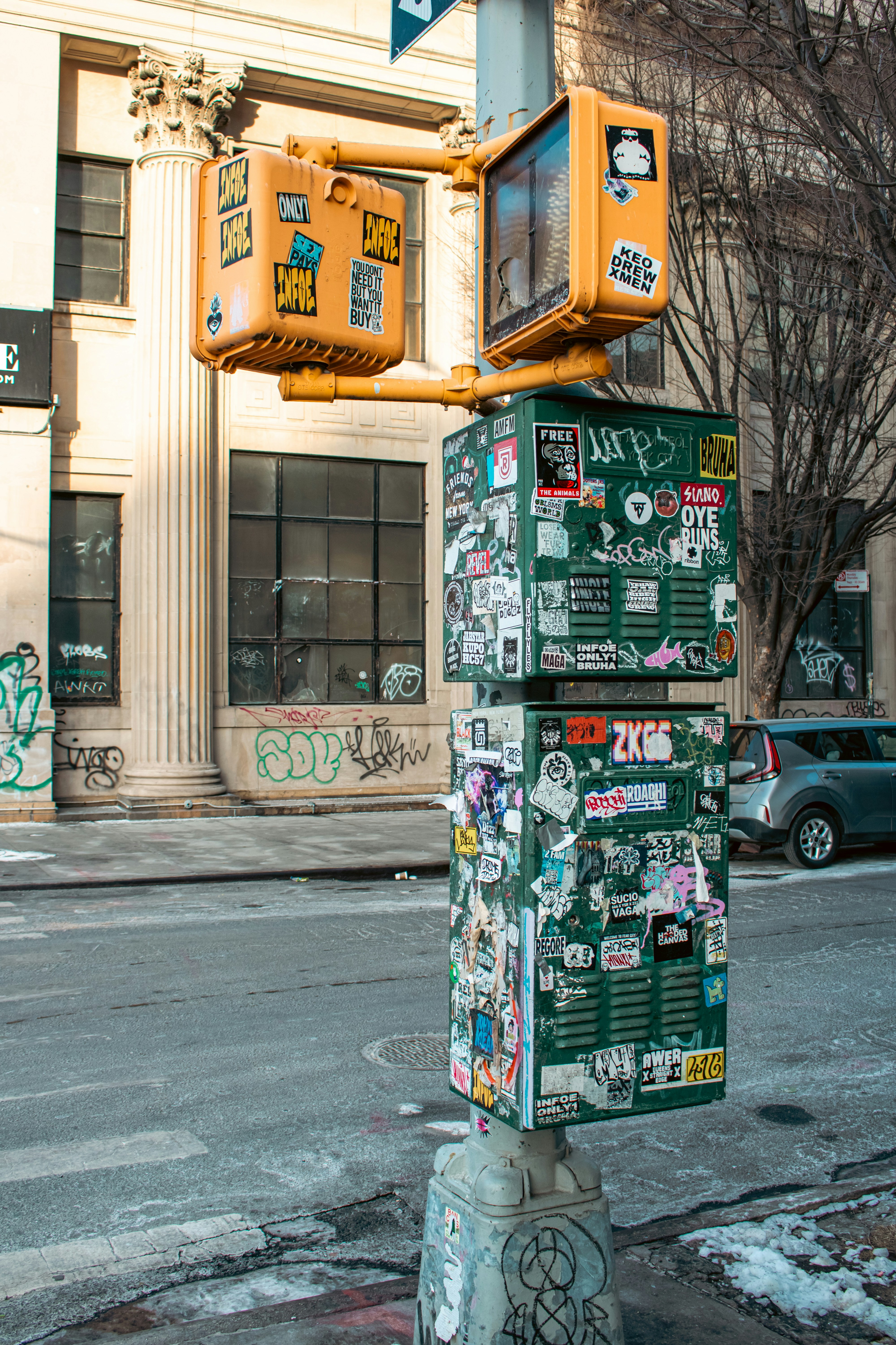 Close-up of a green utility box on a Brooklyn street covered in layers of stickers, graffiti tags, and weathered textures. The colorful chaos of street art contrasts with the urban decay, capturing a raw, authentic slice of New York City sidewalk culture. Faded paper, and hand-drawn tags tell stories of passing artists, skaters, and locals in this gritty street corner scene.