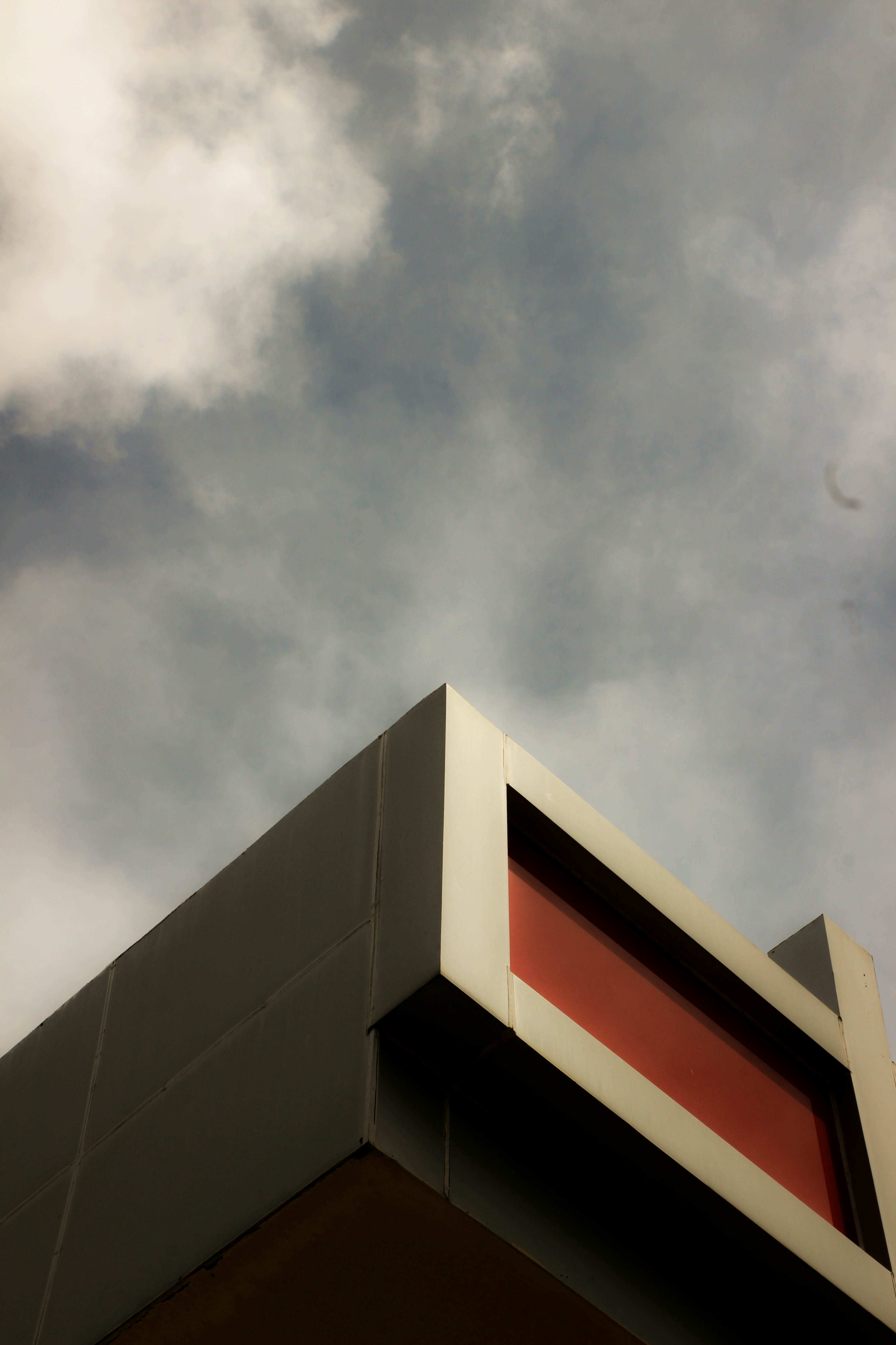 Red-Inset Edge: A Minimalist Building Corner Against a Cloudy Sky
