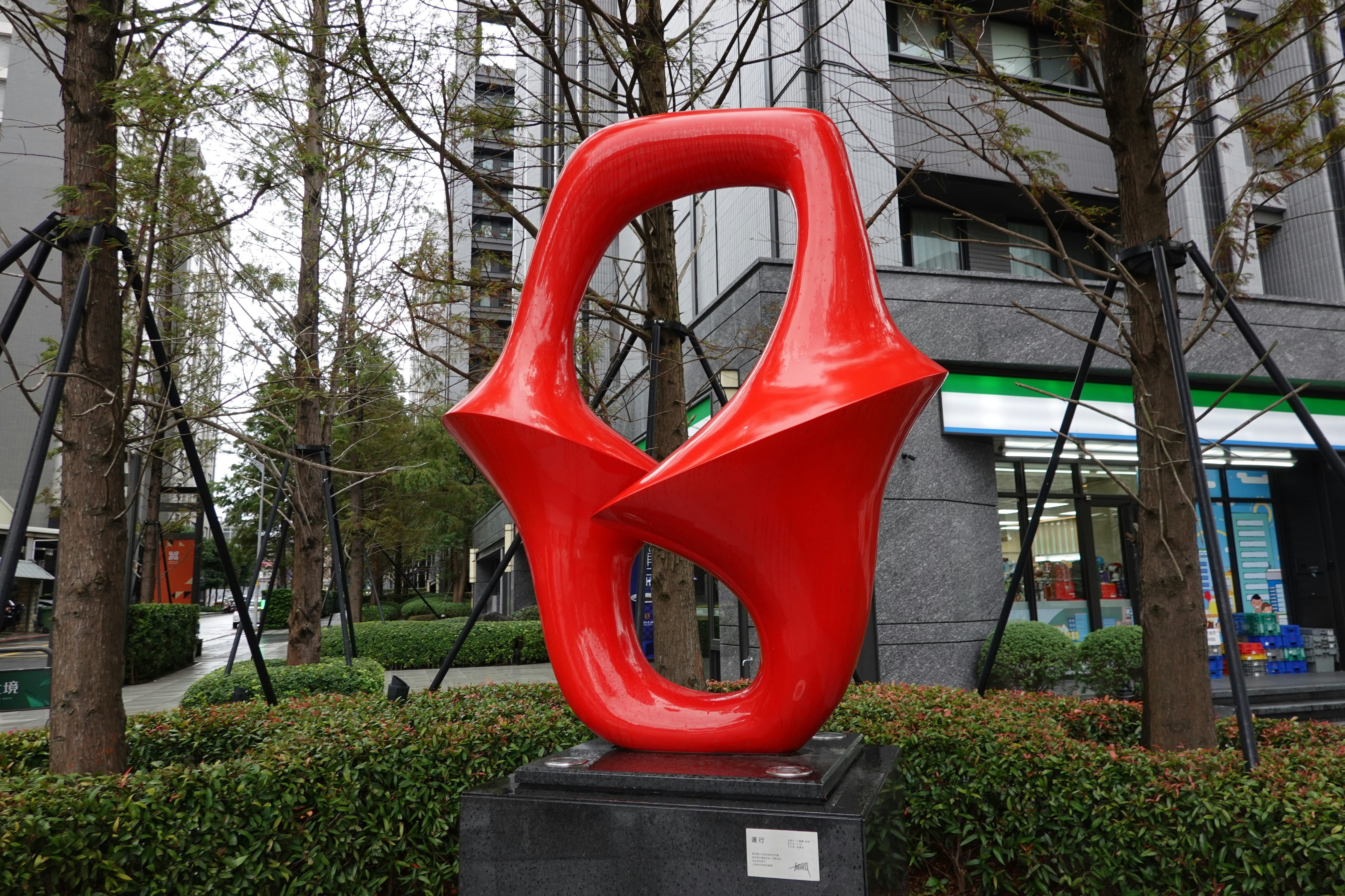 Crimson Loop: An Abstract Sculpture Framed by Urban Green