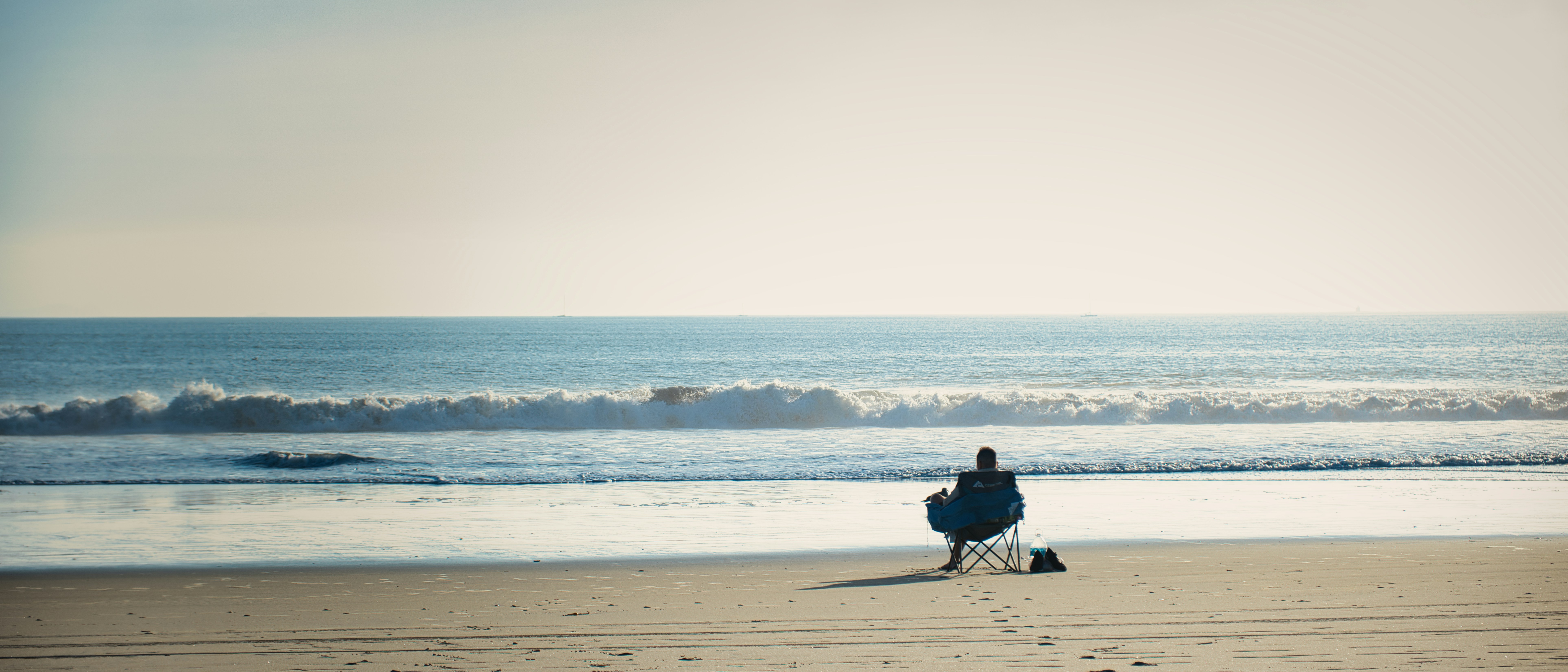 alone man on the Coronado north beach | A surfer heads toward the waves on the beach.