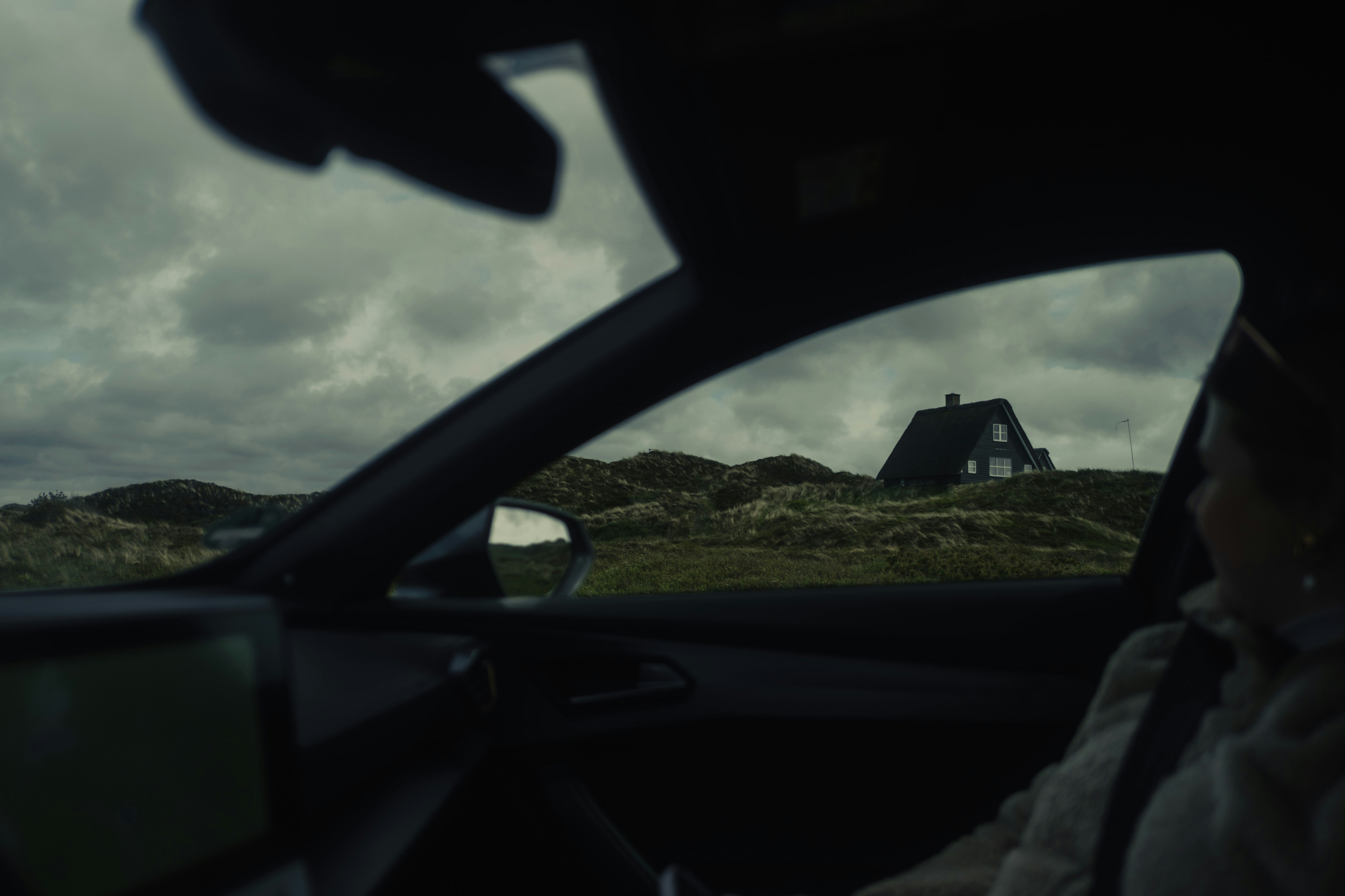 Lone Moor House Framed by a Dim Car Window on a Cloudy Drive