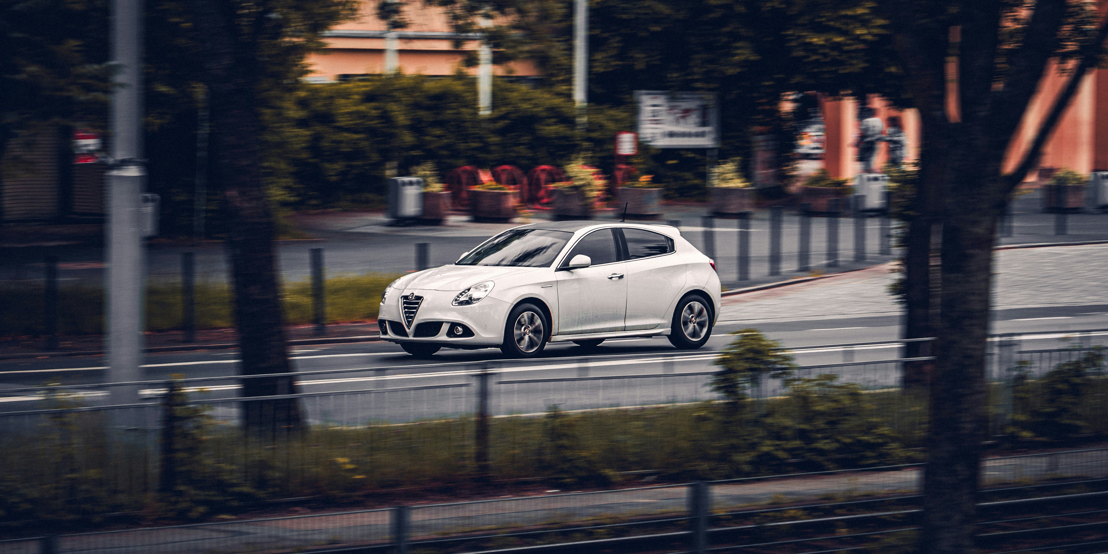 A sleek white car navigates through a city street, embodying the essence of urban mobility and design.