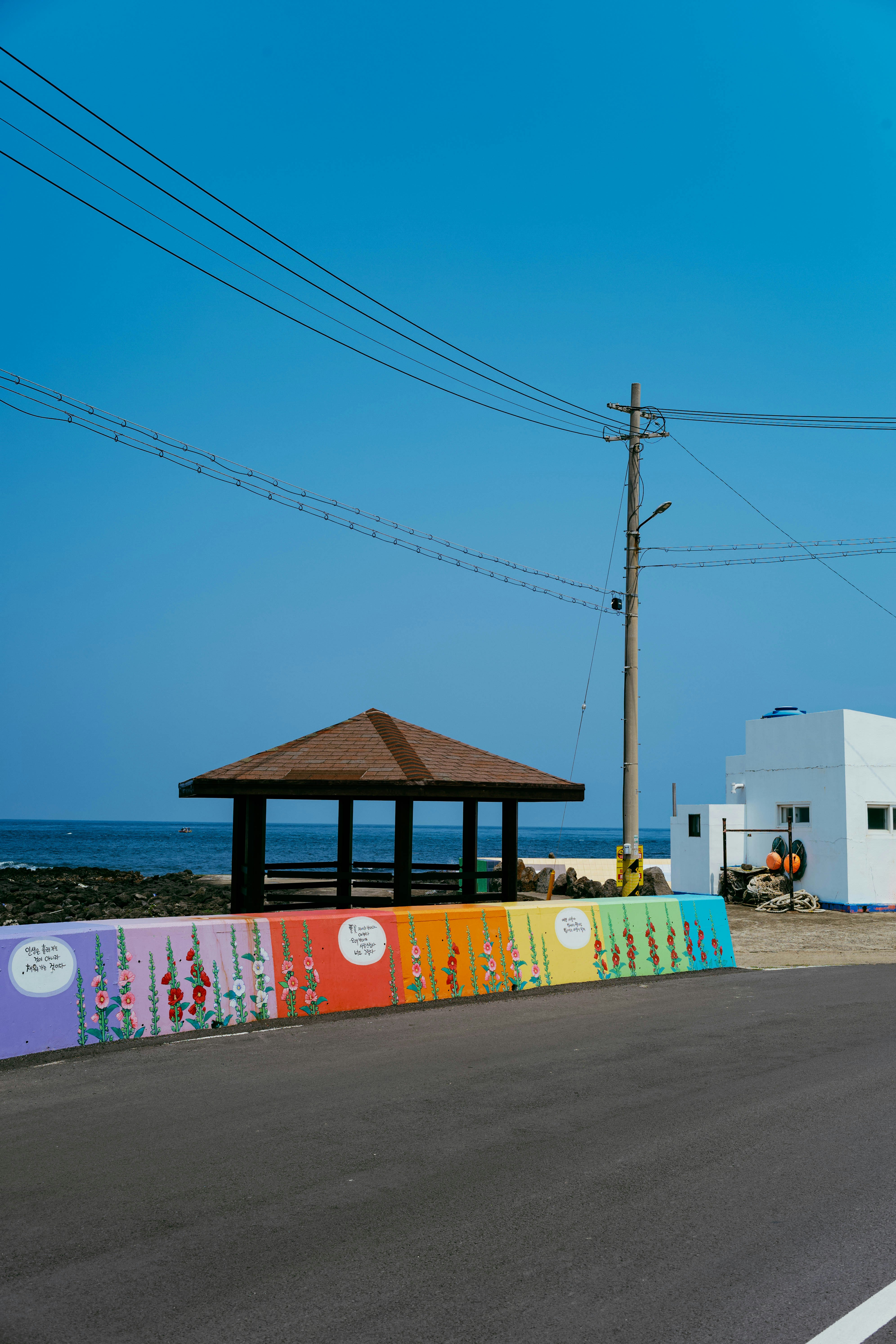 Seaside Pavilion Framed by a Rainbow Wall Under a Clear Coastal Sky