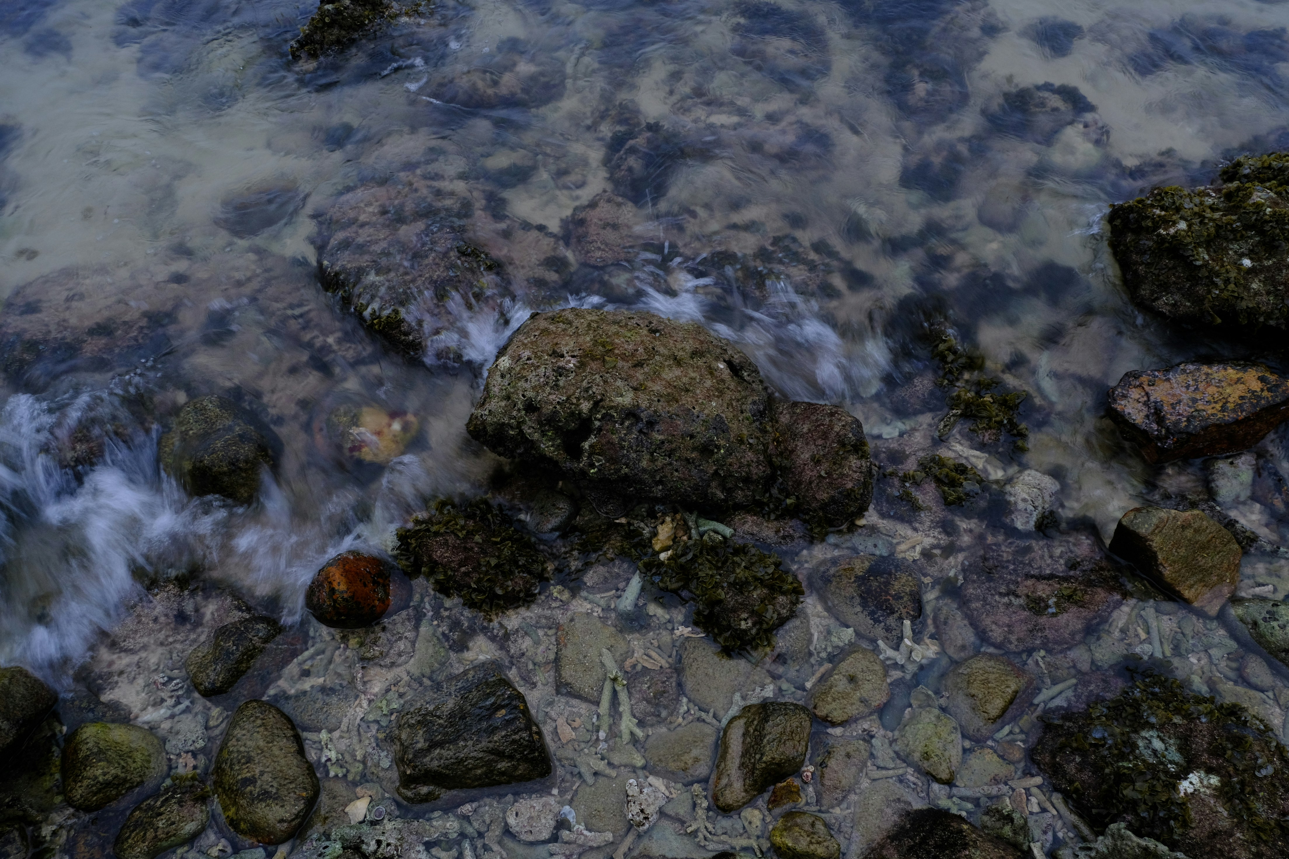 Water gently washes over rocks on a shoreline.