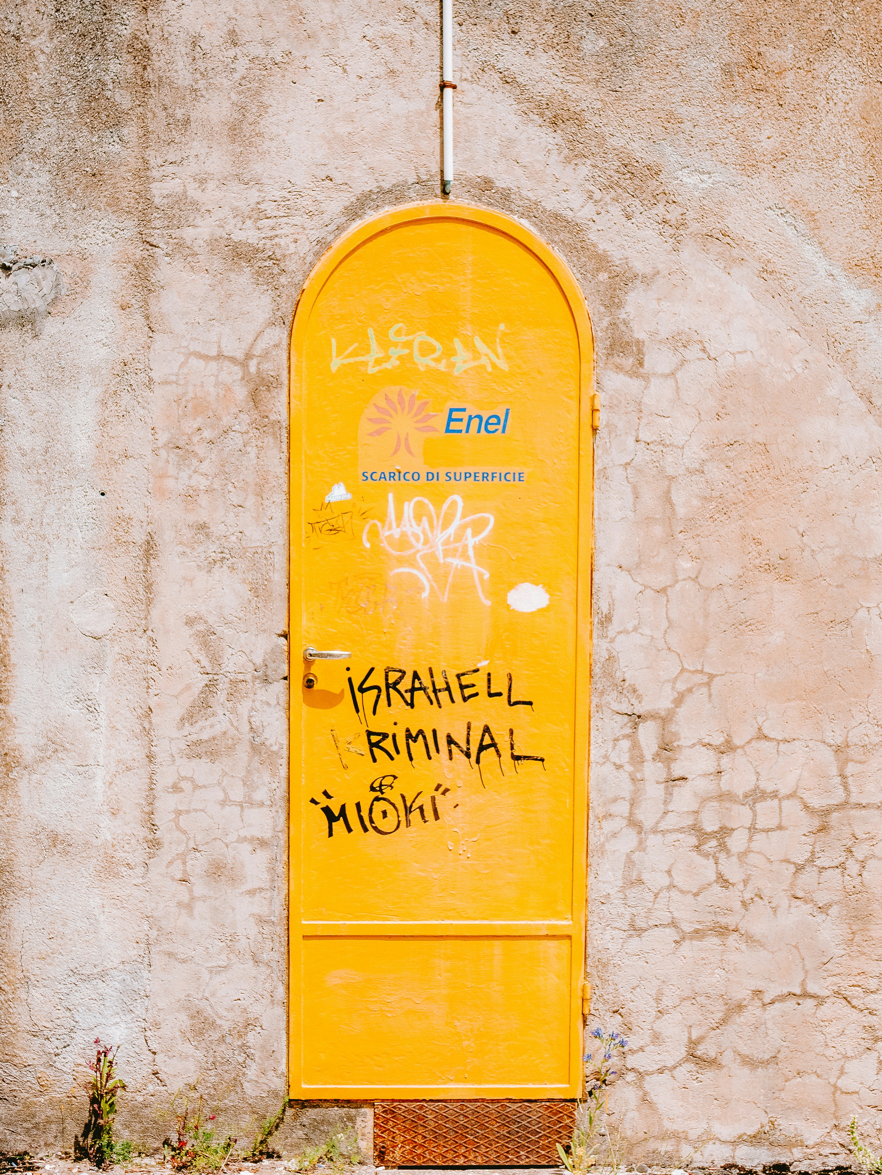 Sun-Burnished Orange Door Framed by Cracked Plaster and Graffiti