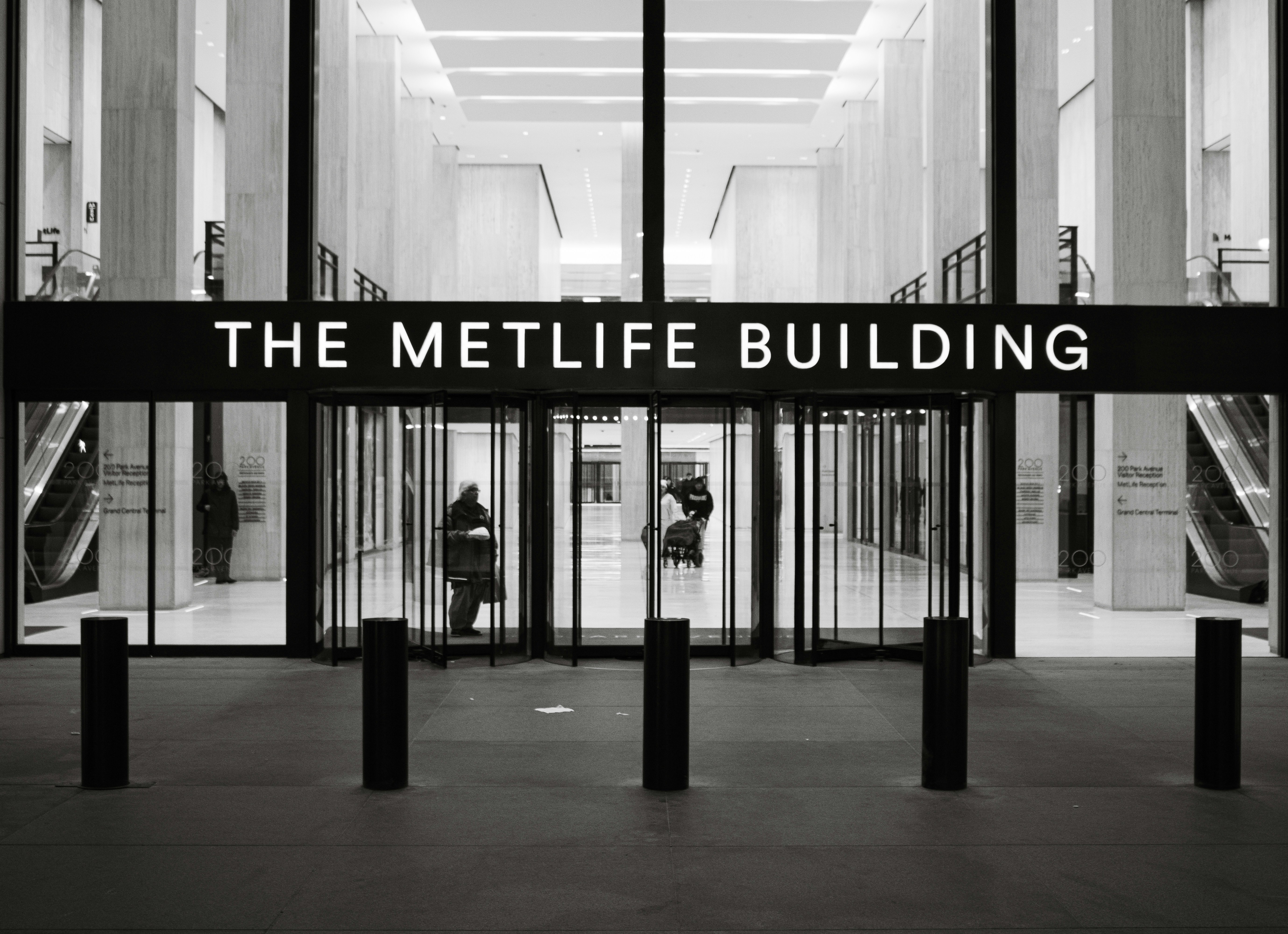 The MetLife Building entrance showcases sleek architecture and modern design, inviting visitors into a spacious interior. The monochromatic palette emphasizes the building's grandeur.