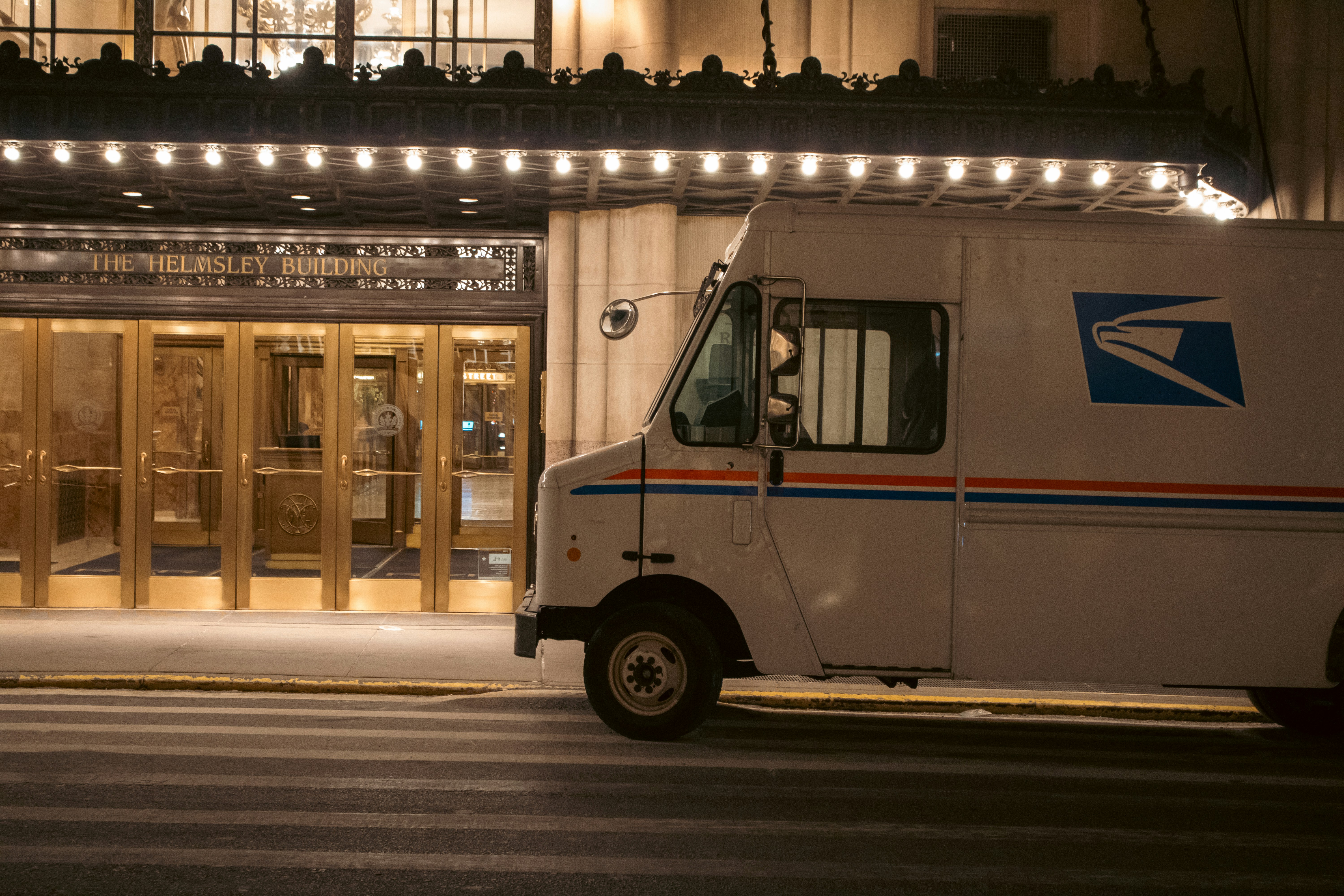 Marquee Glow by Night: A USPS Truck Resting Outside The Helmsley Building