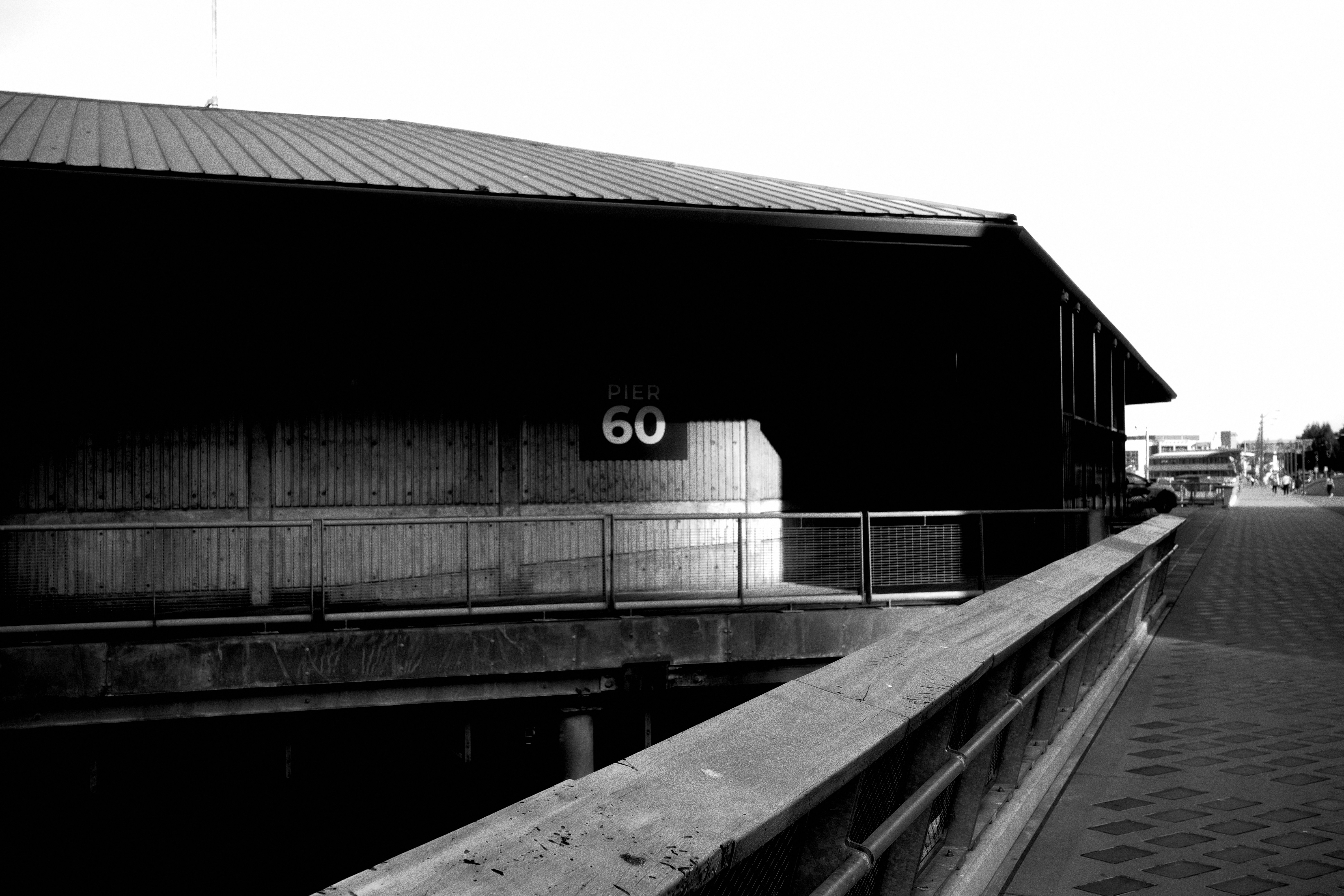 Monochrome view of Pier 60 with a focus on the architectural lines and textures of the building. The number '60' stands out against the dark wood backdrop.