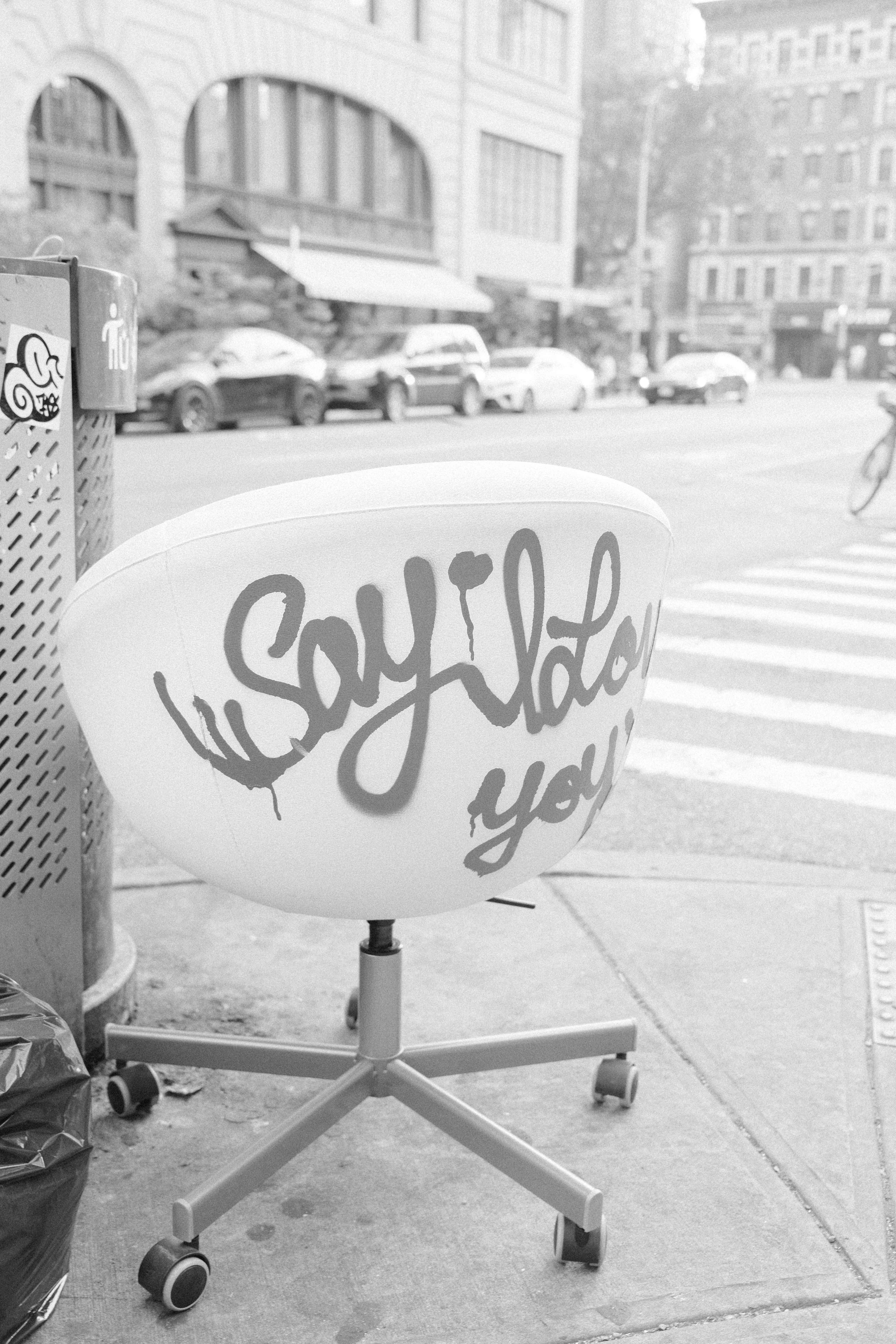 Chair with "say i love you" graffiti in the street.
