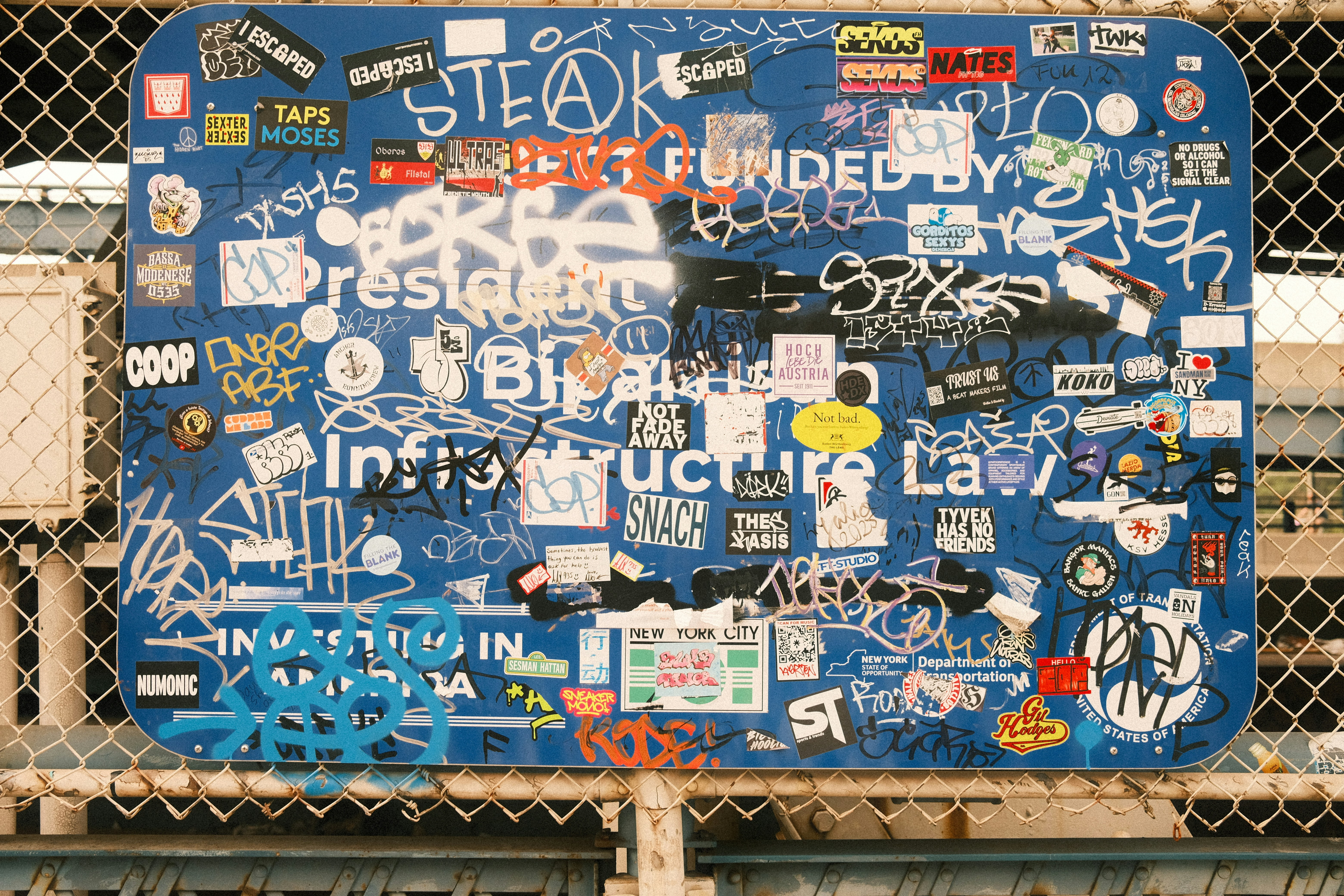 A vibrant collage of stickers and graffiti on a blue backdrop, showcasing the eclectic nature of urban art and expression.