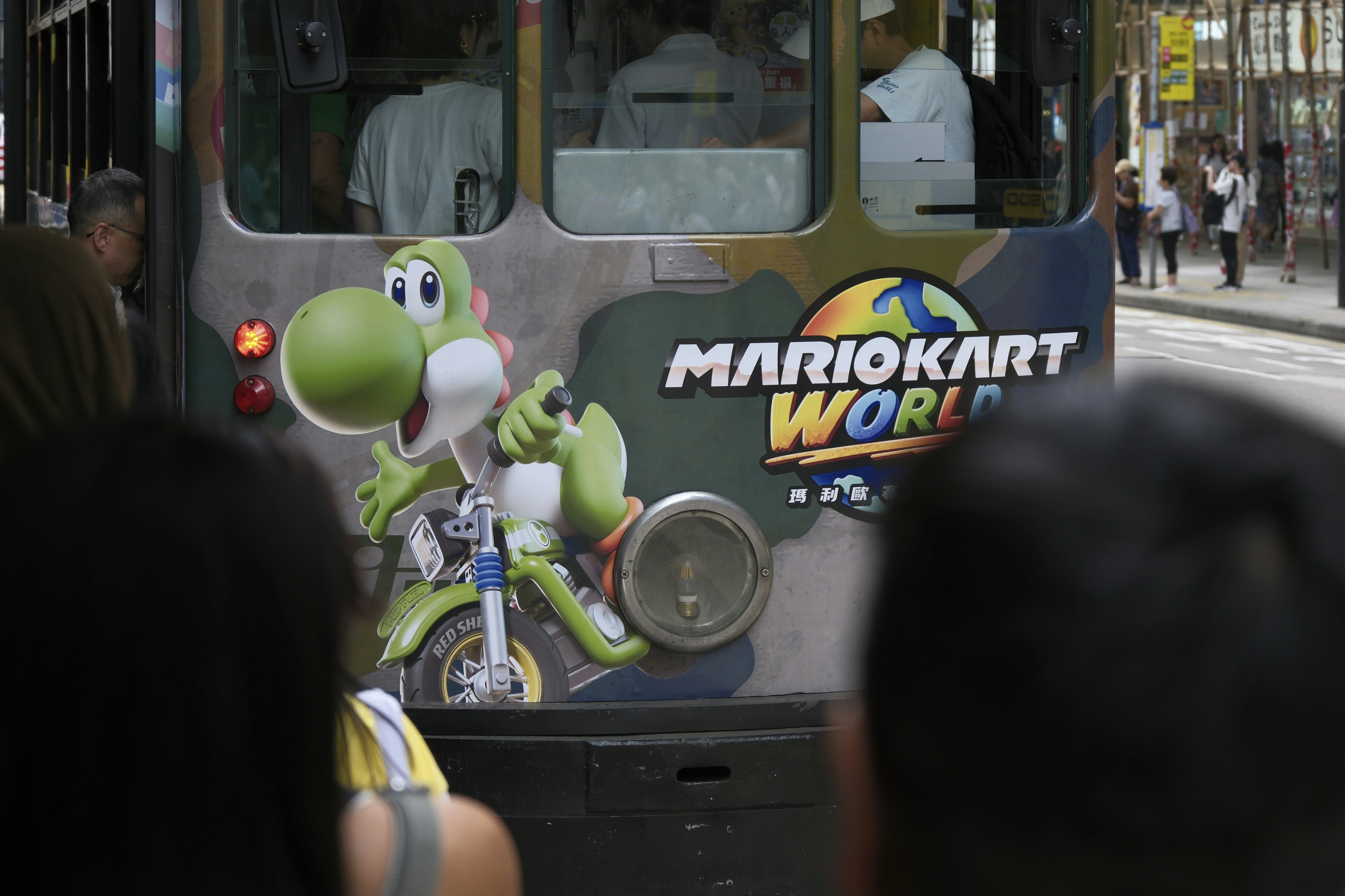 Yoshi on a bus promoting mario kart world. photo – Free Woman Image on ...