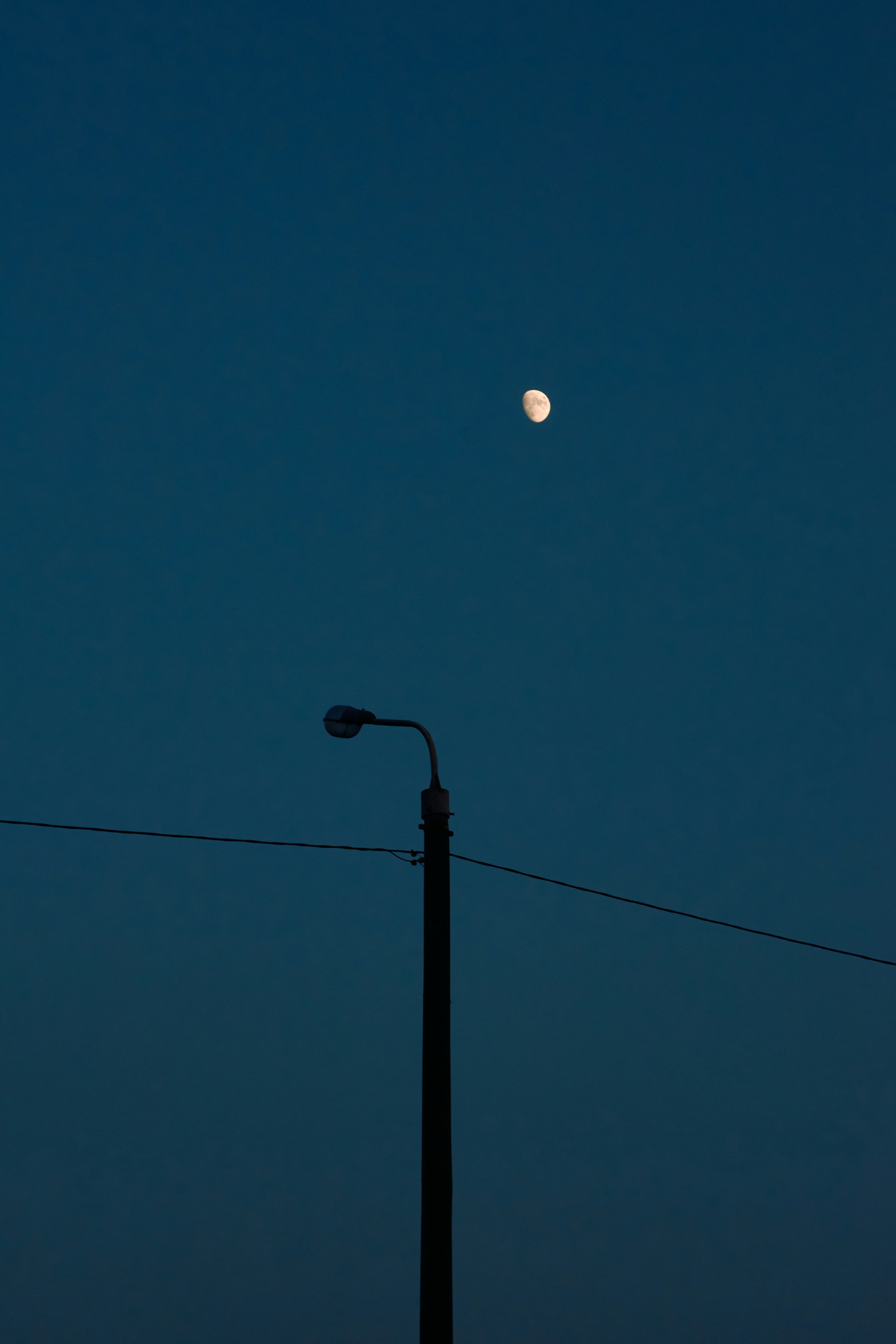 The moon shines above a street lamp.