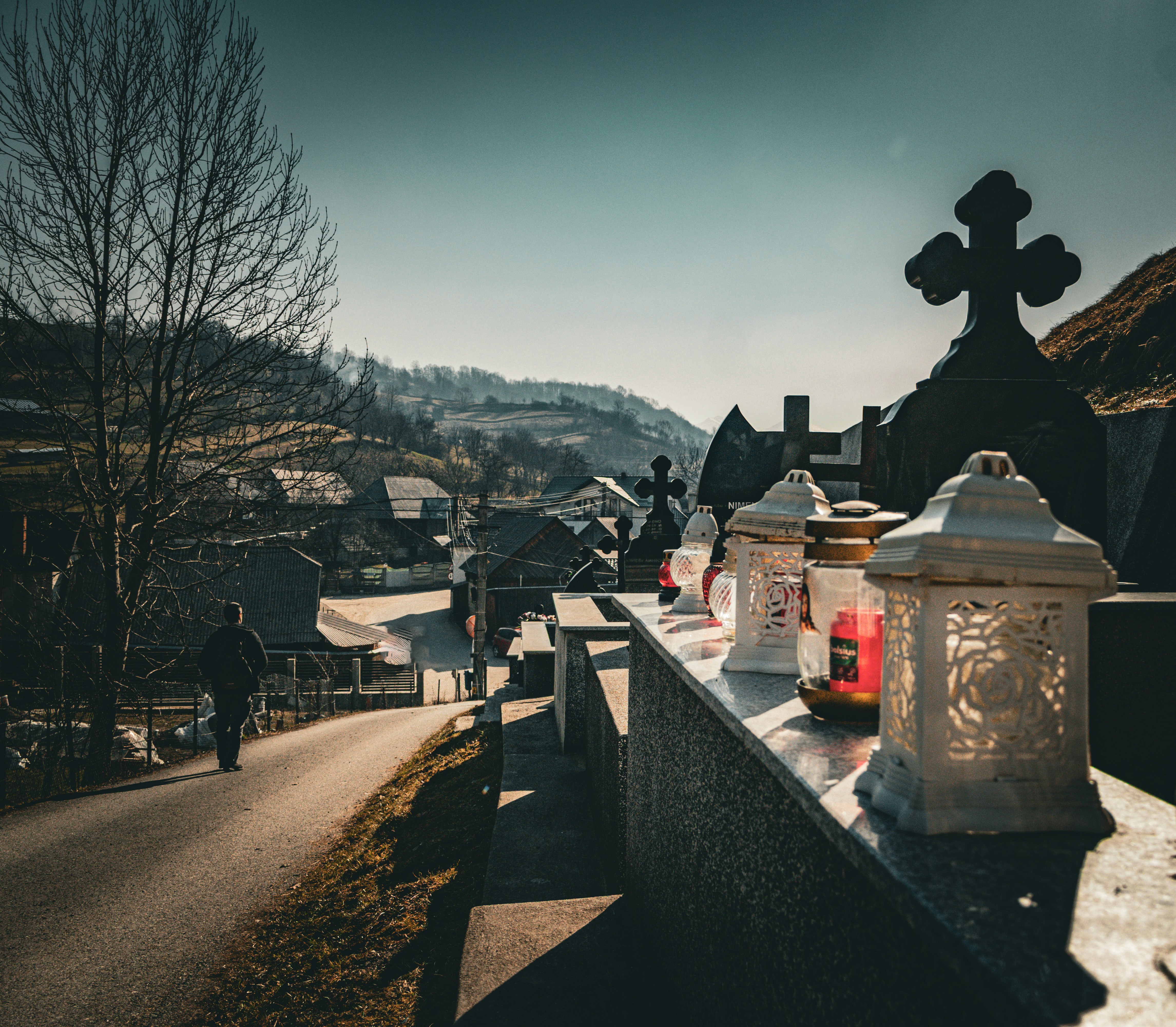 A person walks by a cemetery on a sunny day.