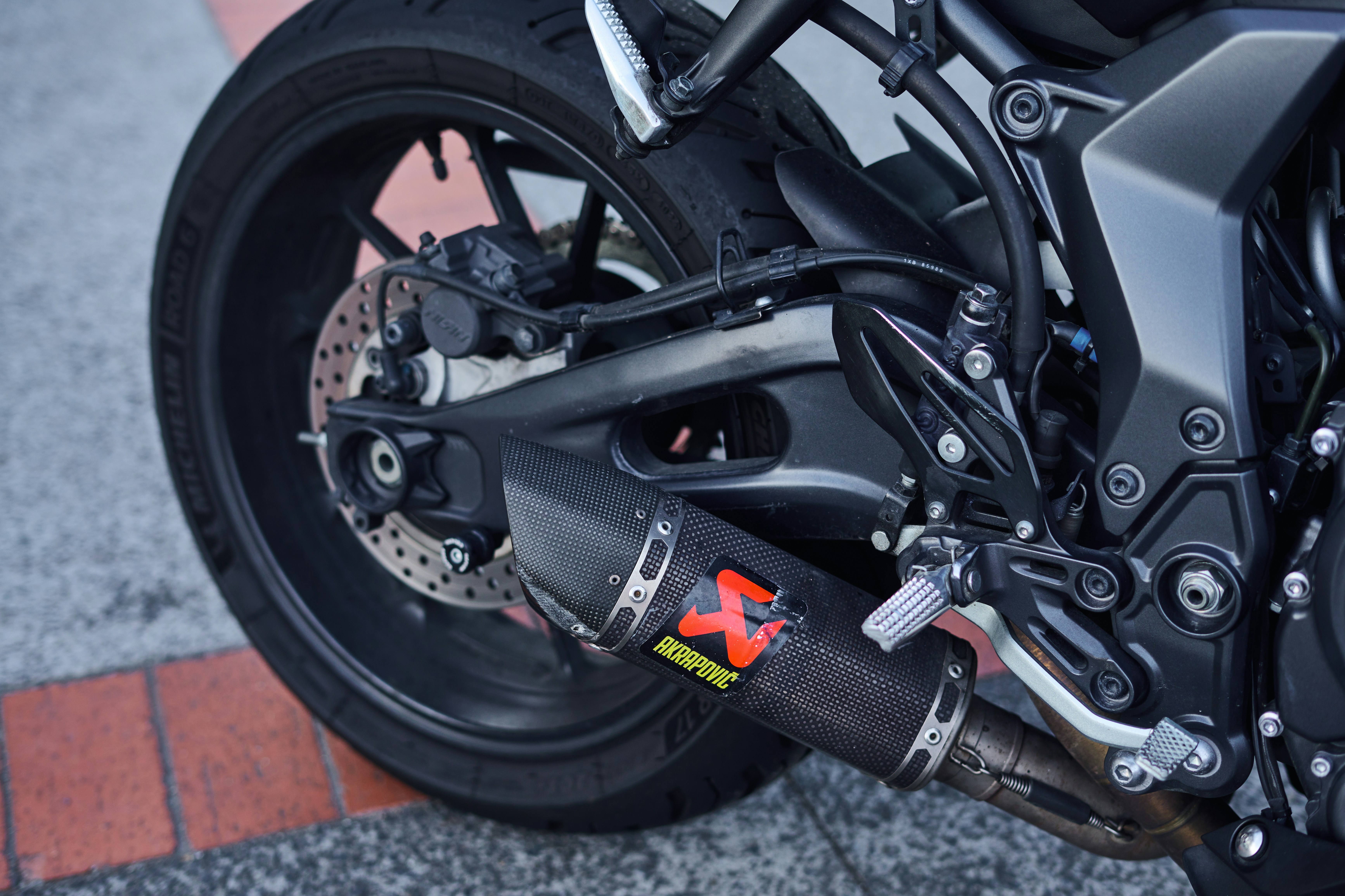 Detailed view of a motorcycle's rear wheel and exhaust system, showcasing intricate engineering and design elements.