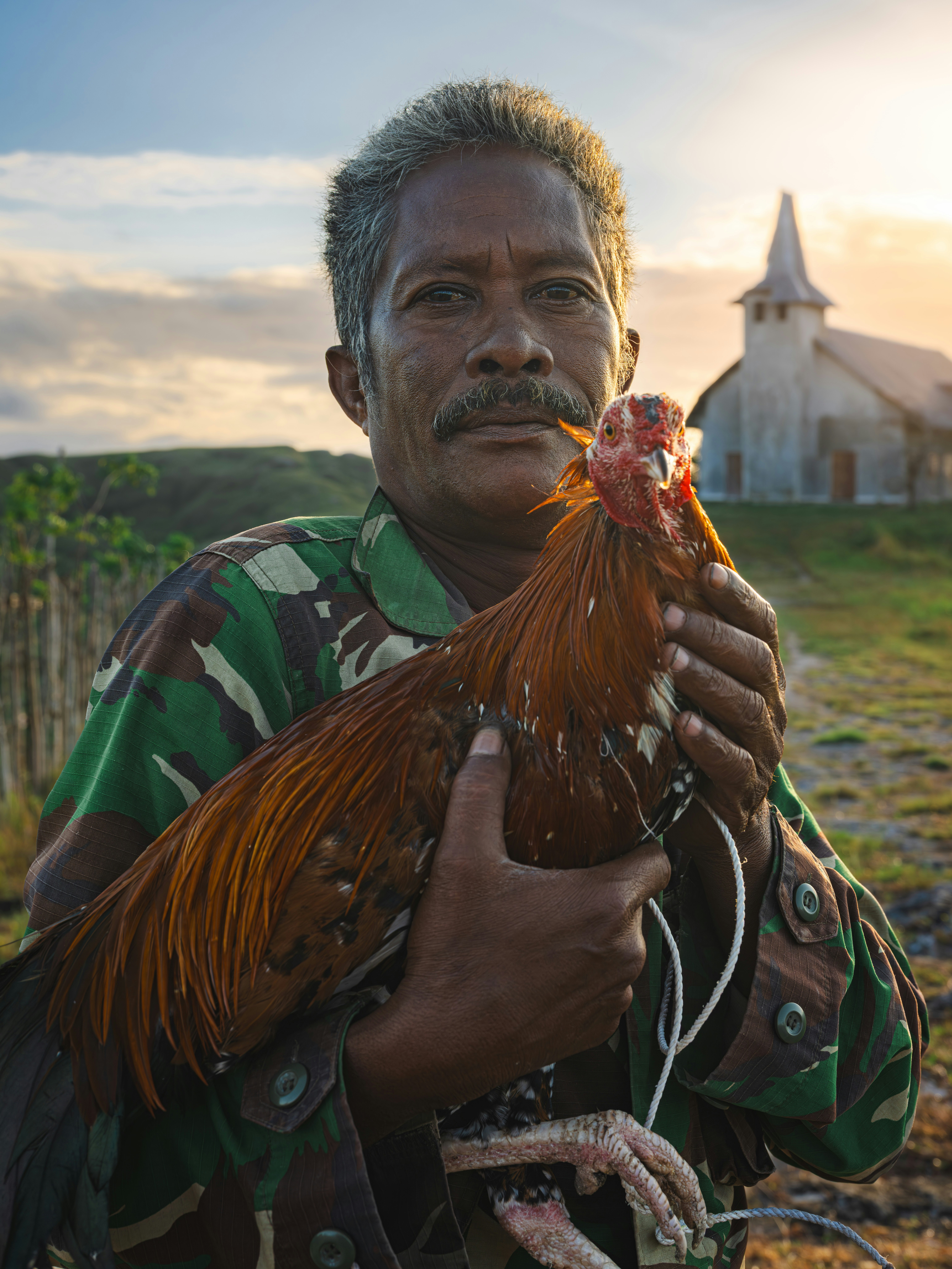 A man holds a rooster in front of a church. photo – Free Portrait Image ...