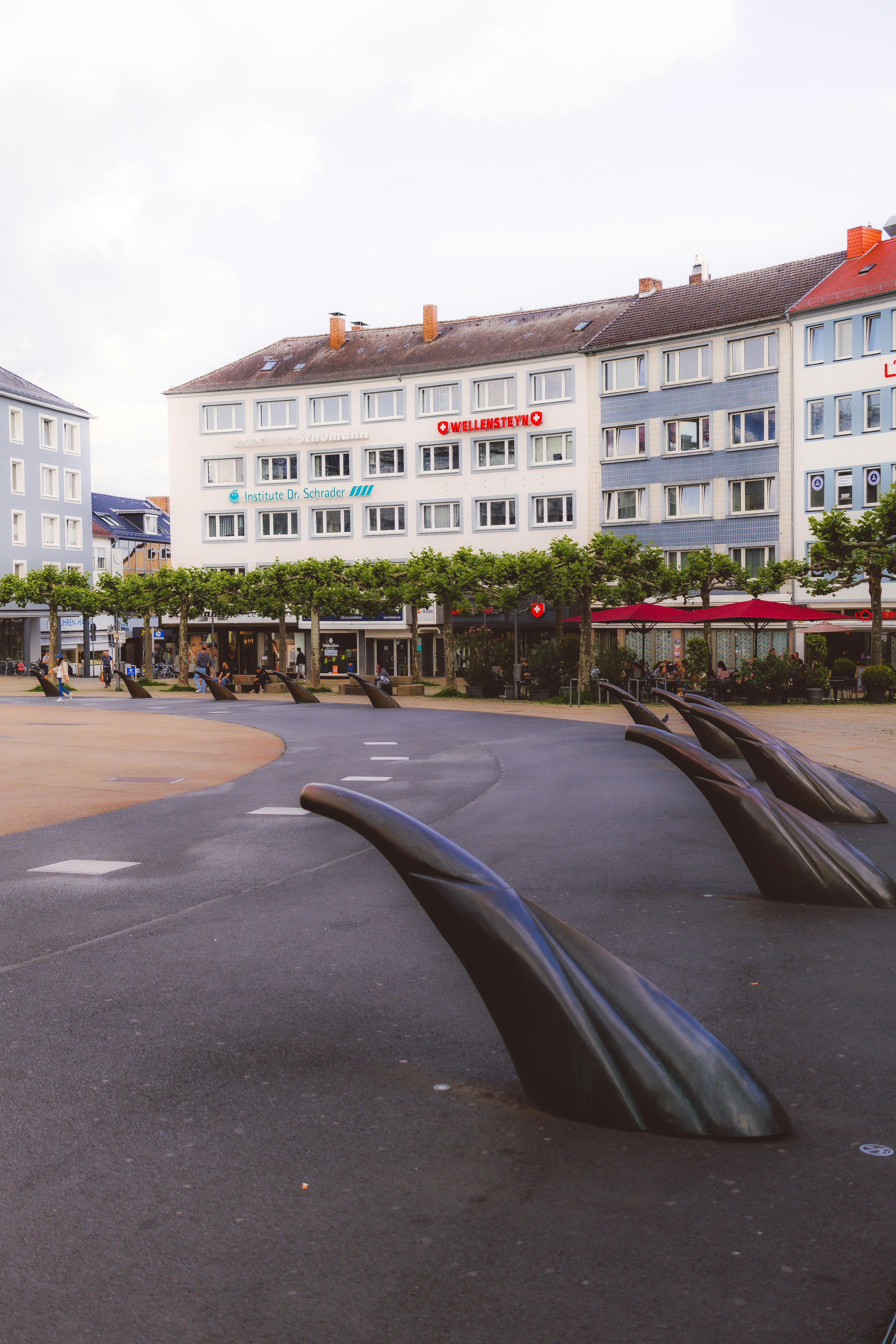 Sculptures grace a town square near a building.