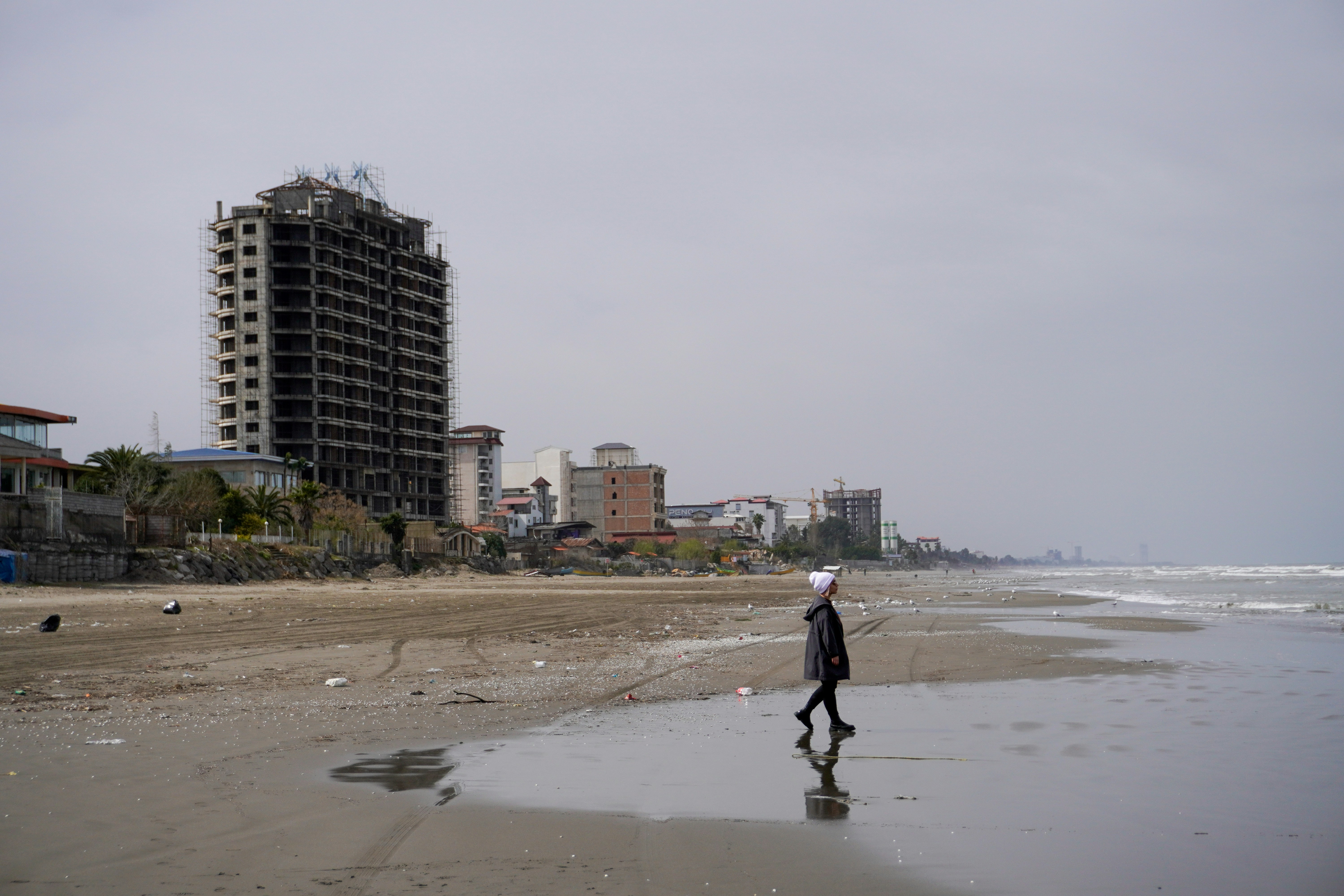 A person walks on a rainy beach.