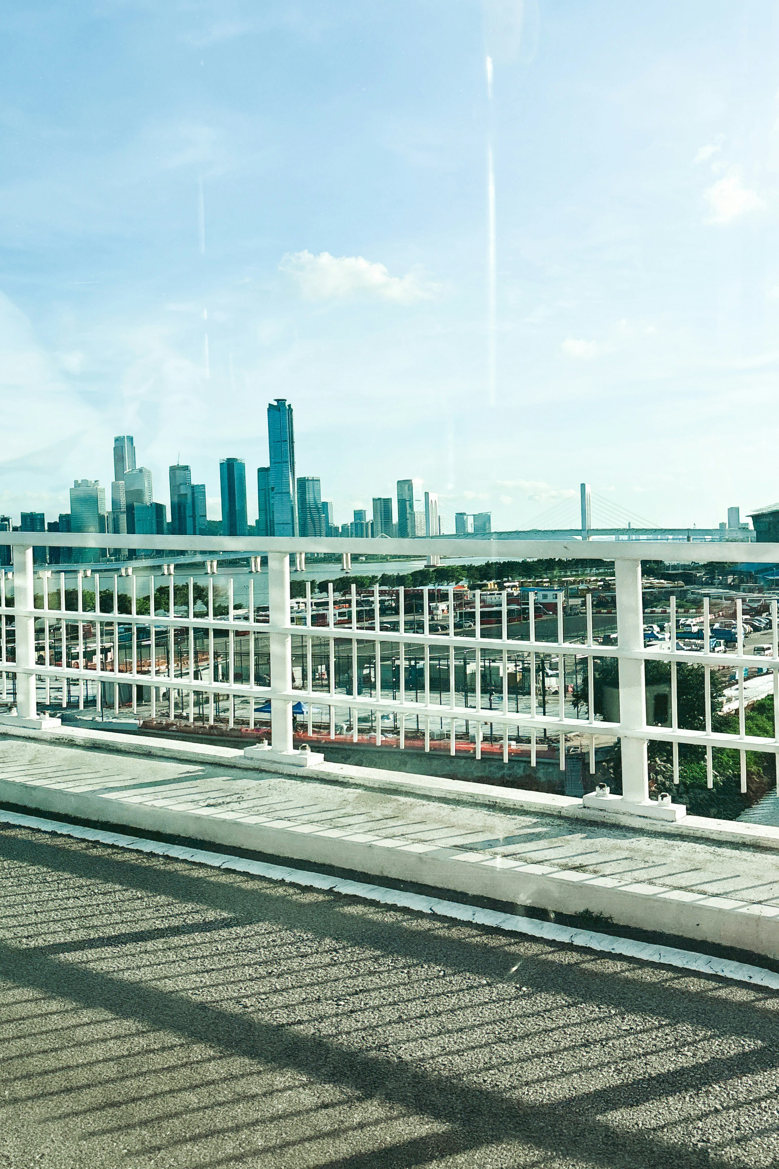 A cityscape is viewed from a bridge with a railing. photo – Free Road ...