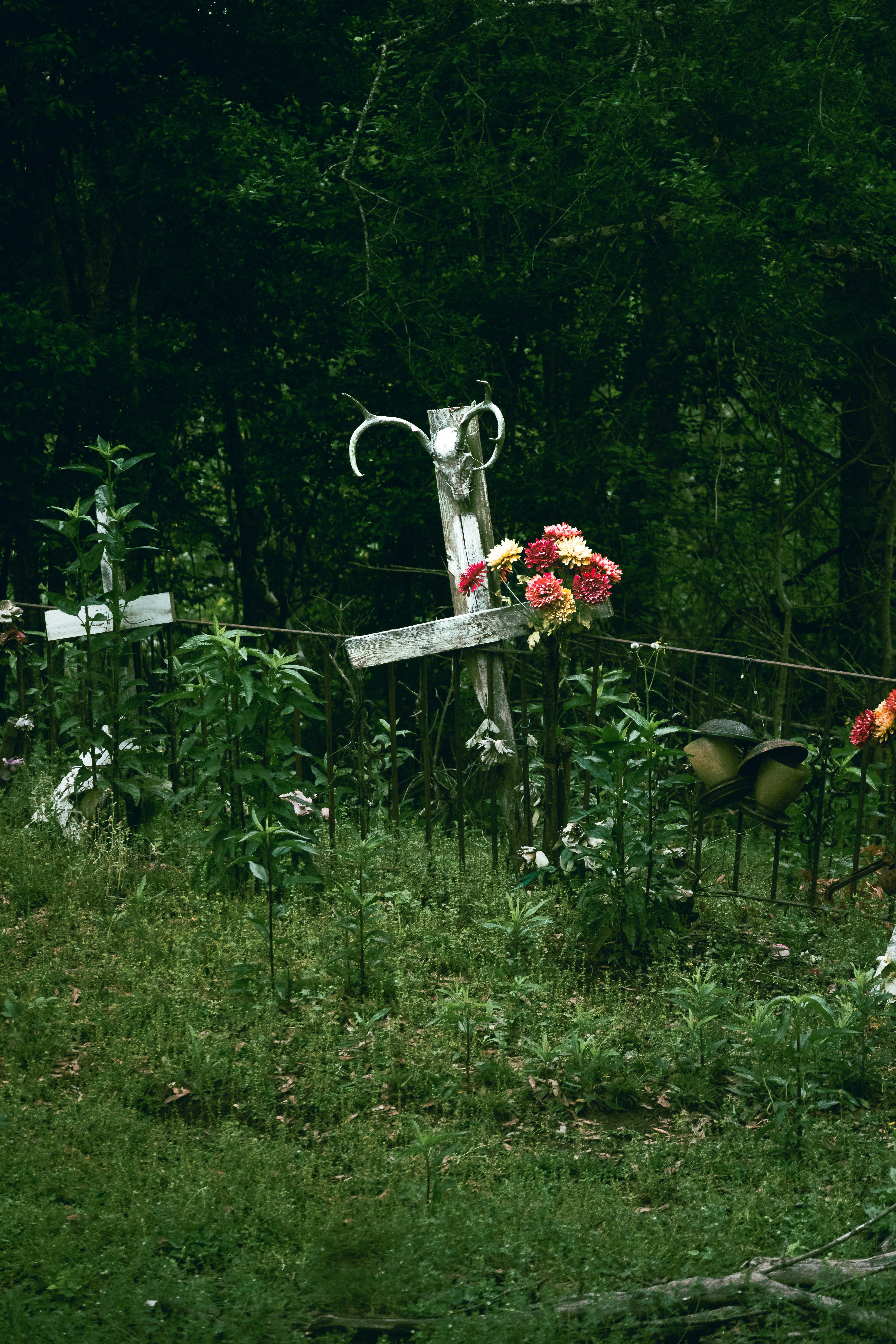 Weathered Cross Adorned with Bouquets in a Quiet Cemetery Garden