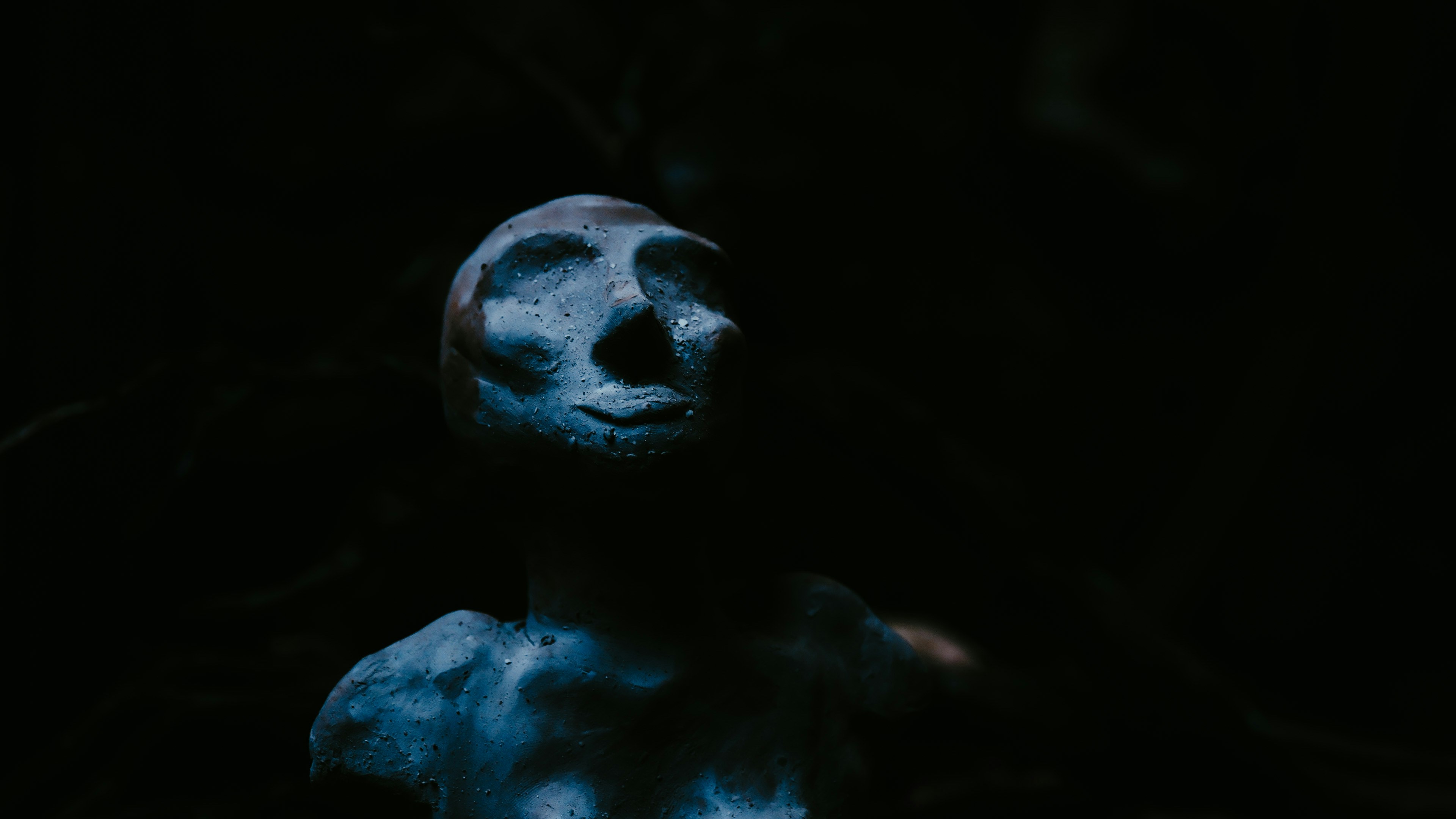 A blue statue glows in the dark.
