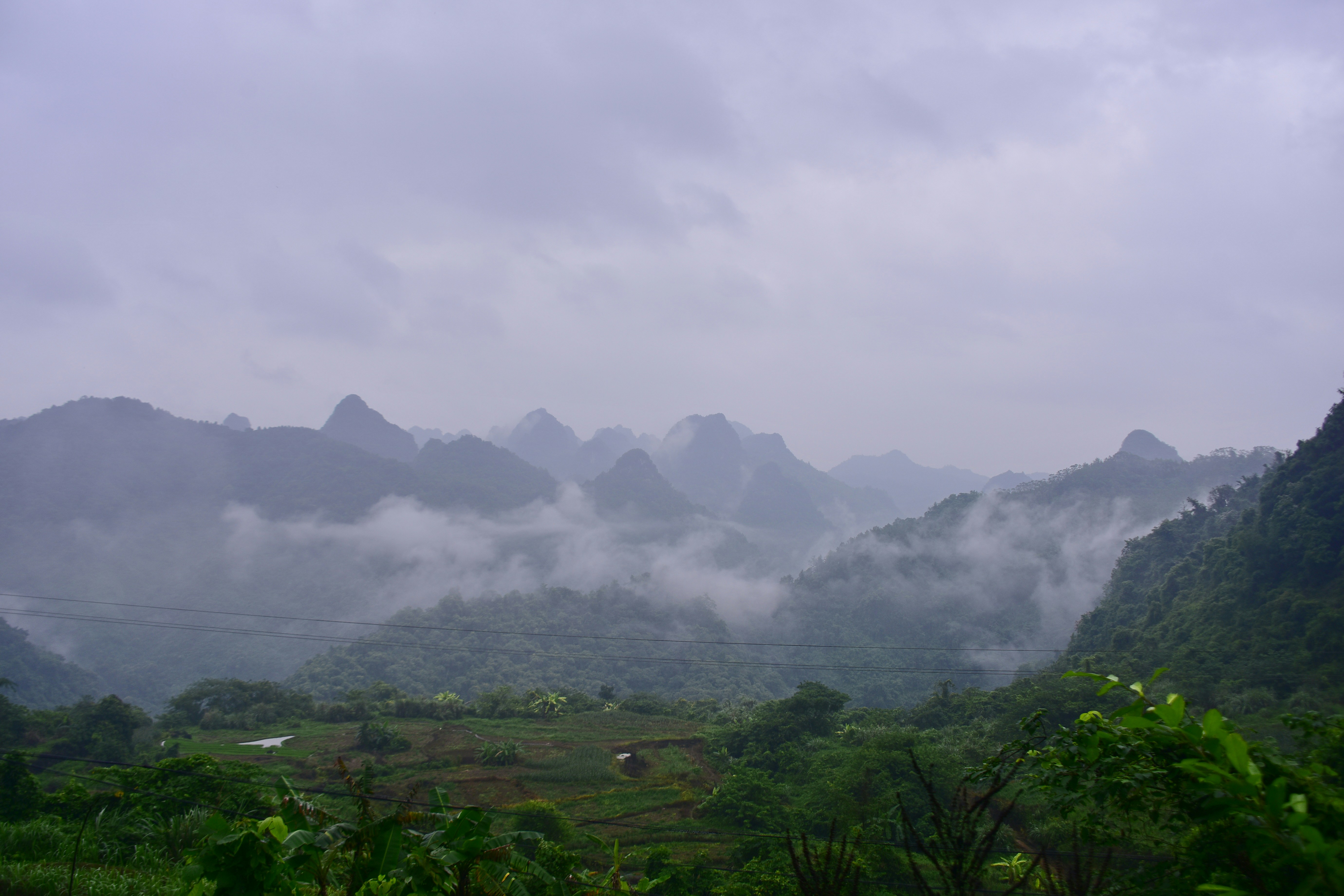 Foggy mountains and green valleys under a cloudy sky.