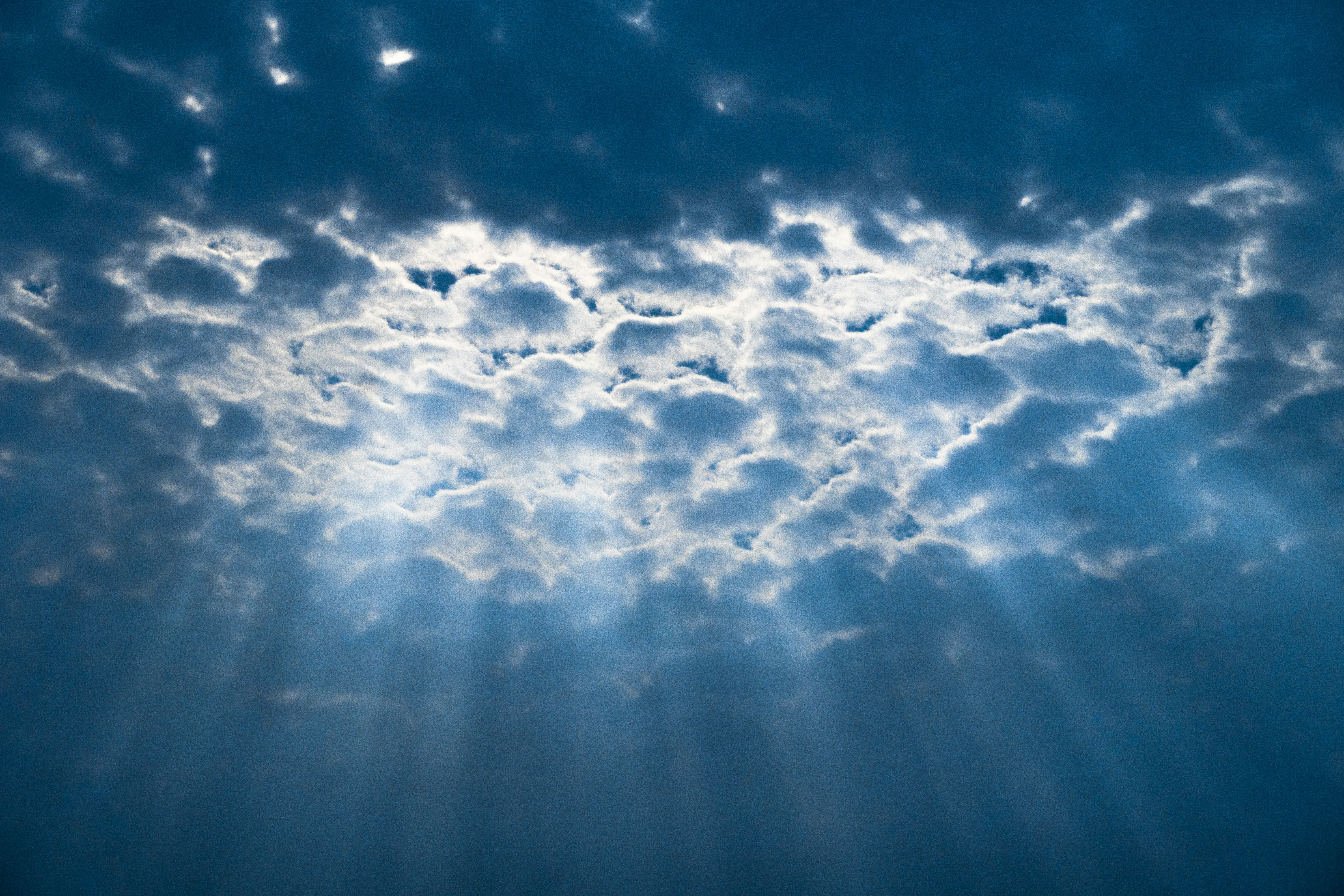 Cobalt Sky Pierced by Silent Sunbeams Through Cloud Veil