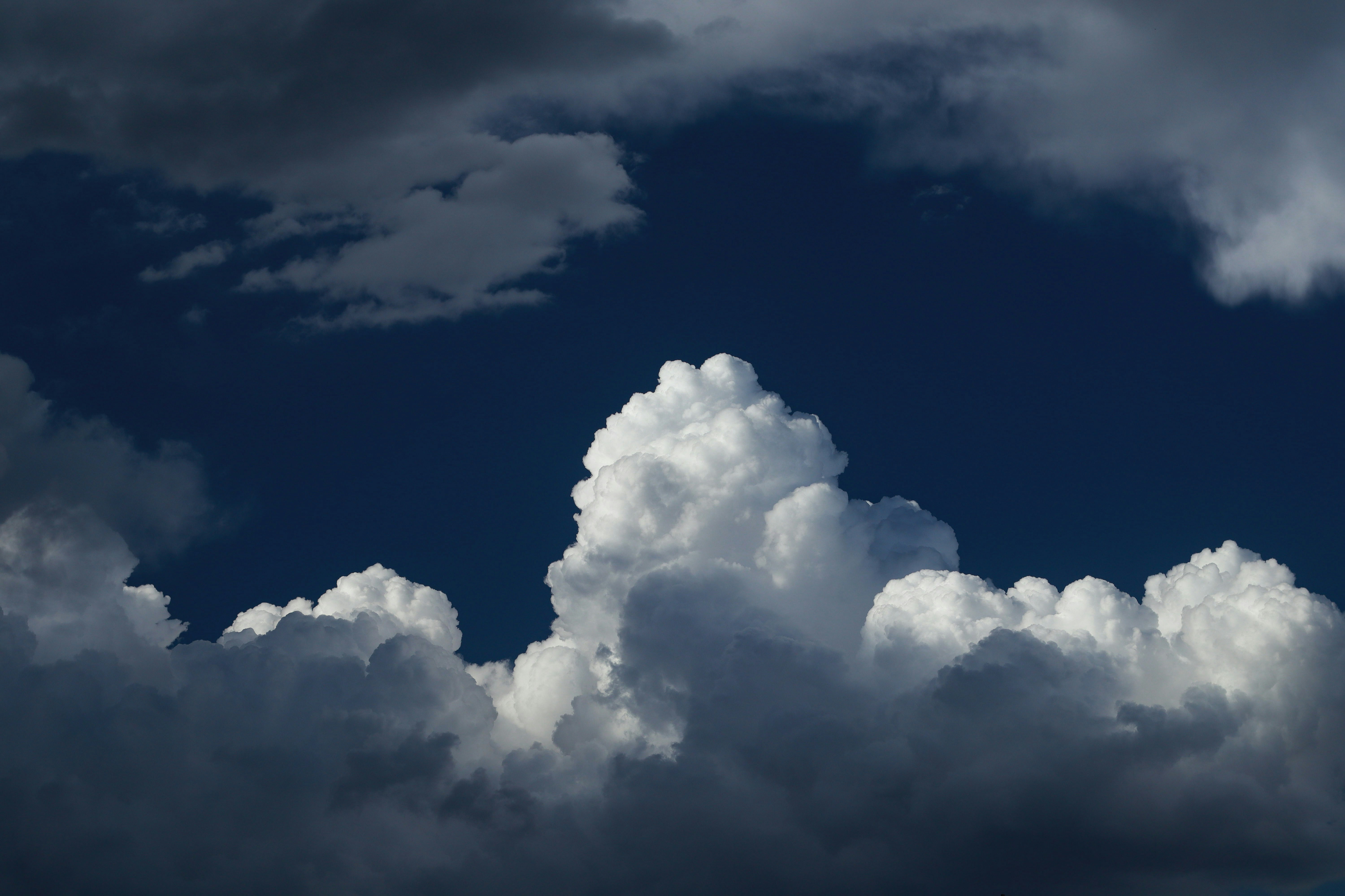 Dramatic clouds illuminated against a deep blue sky, creating a dynamic interplay of light and shadow.