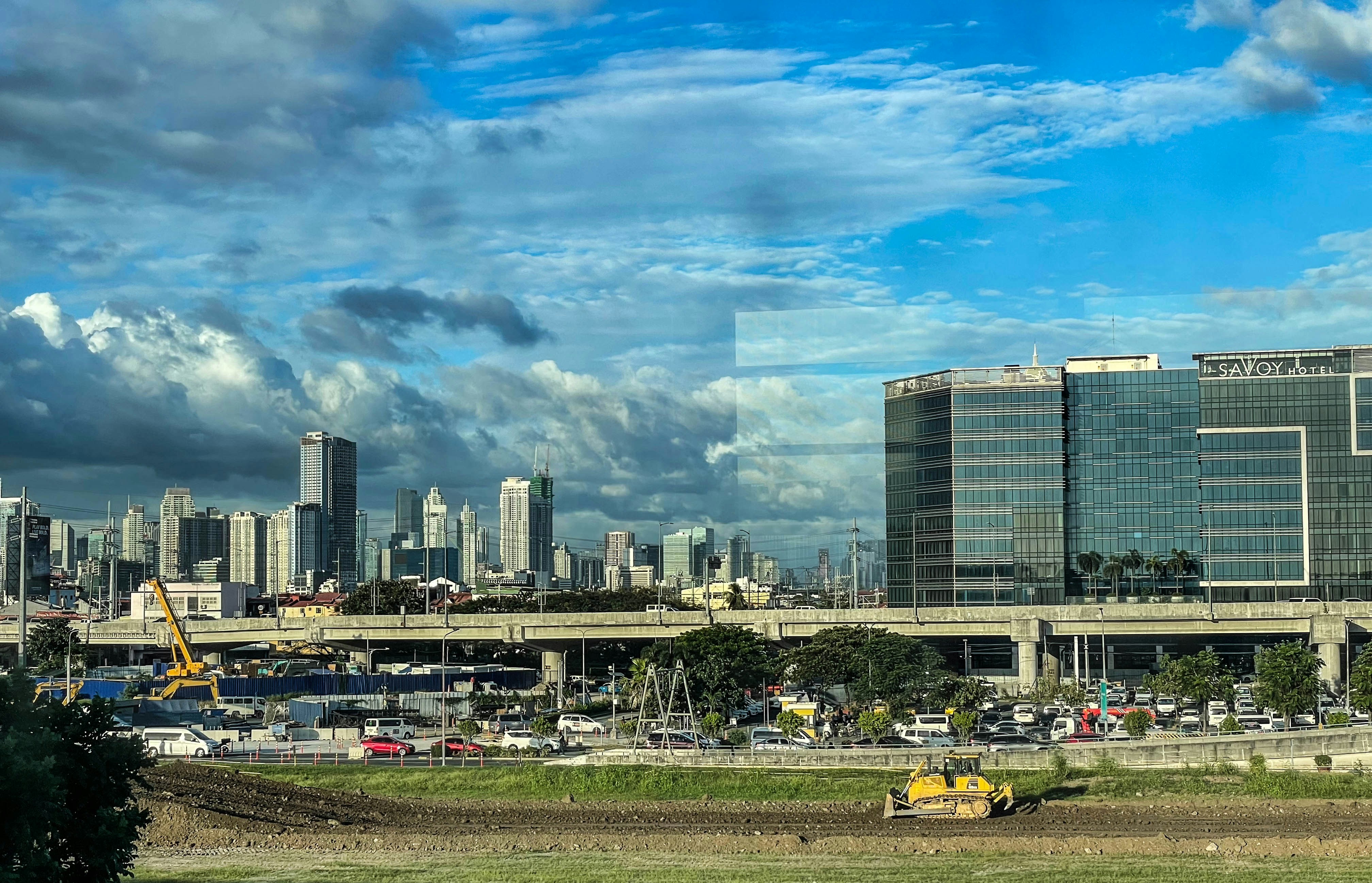 A vibrant cityscape showcasing a blend of modern architecture and construction activity under a dramatic sky.