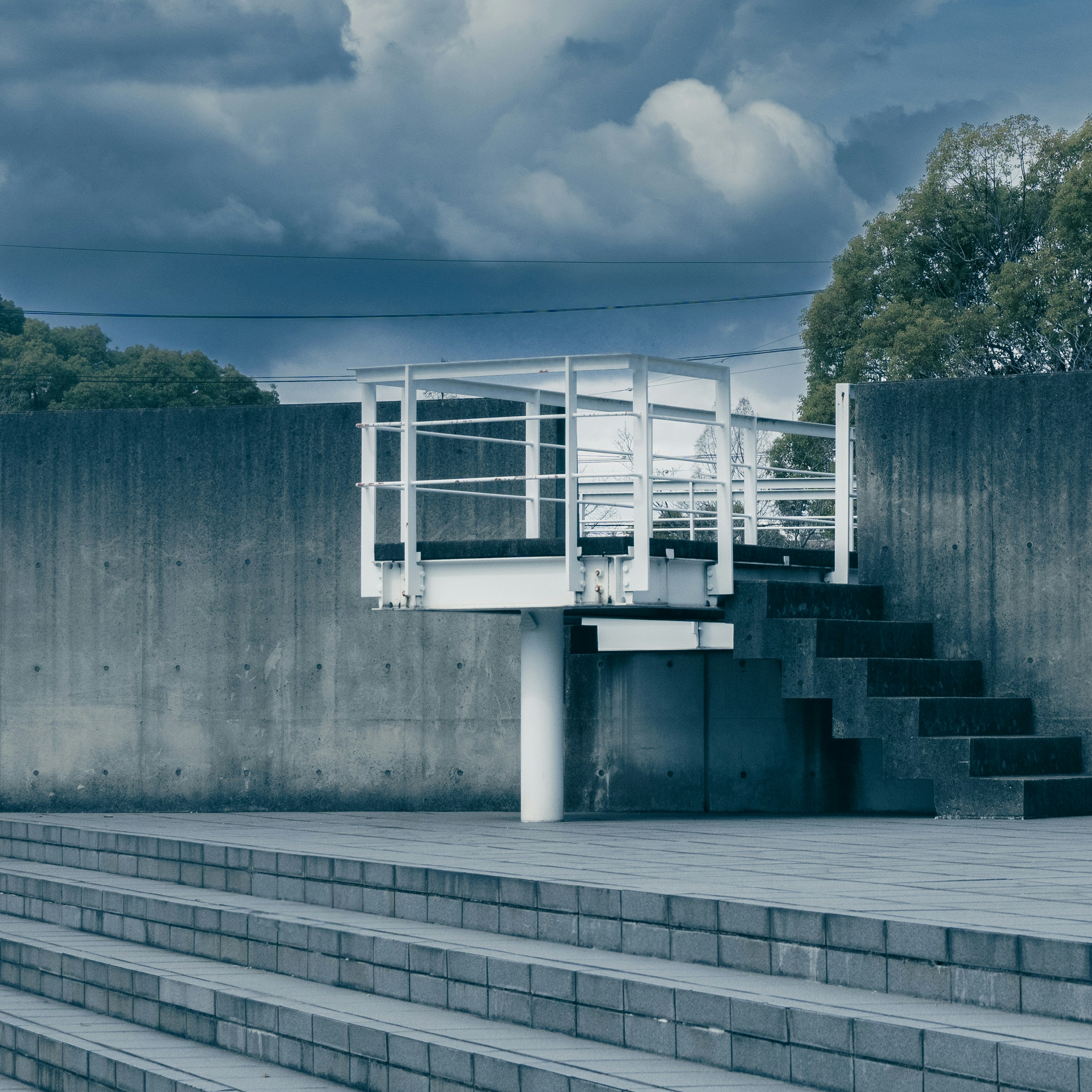 Riser and Rail: A White Platform Framed by Stairs Beneath Stormy CloudsSteven Lynn