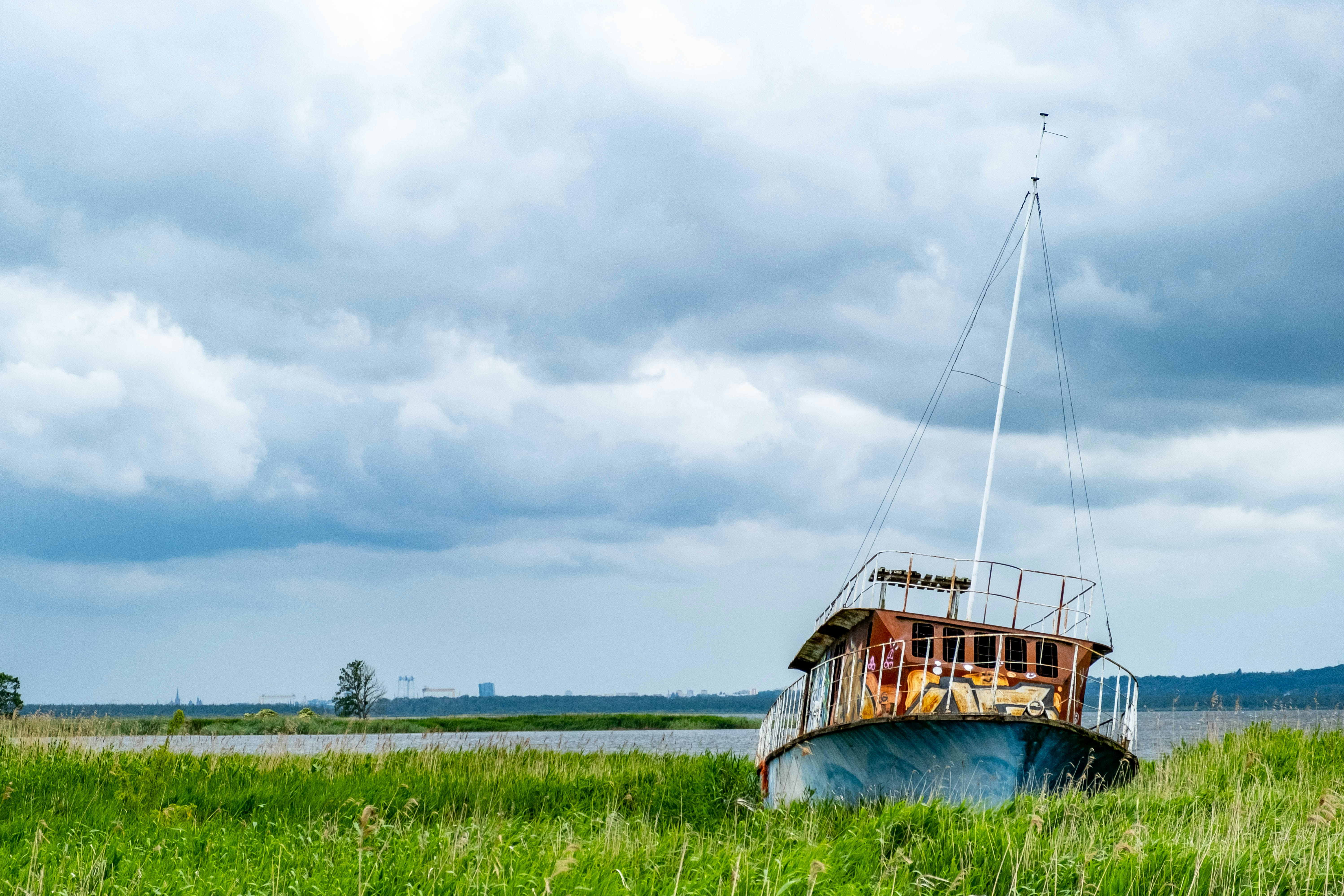 Sailboat Stranded in a Verdant Marsh Under a Cloudy Sky