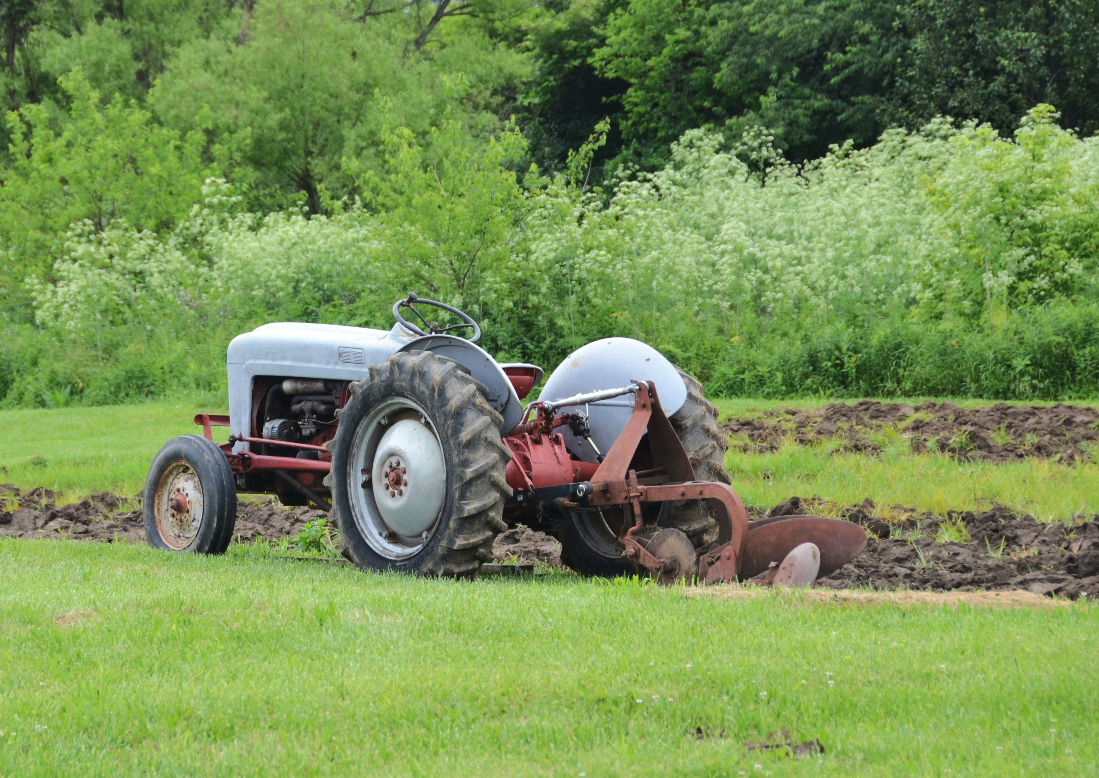 Farmer works on a stuck tractor in a field. photo – Free Grass Image on ...