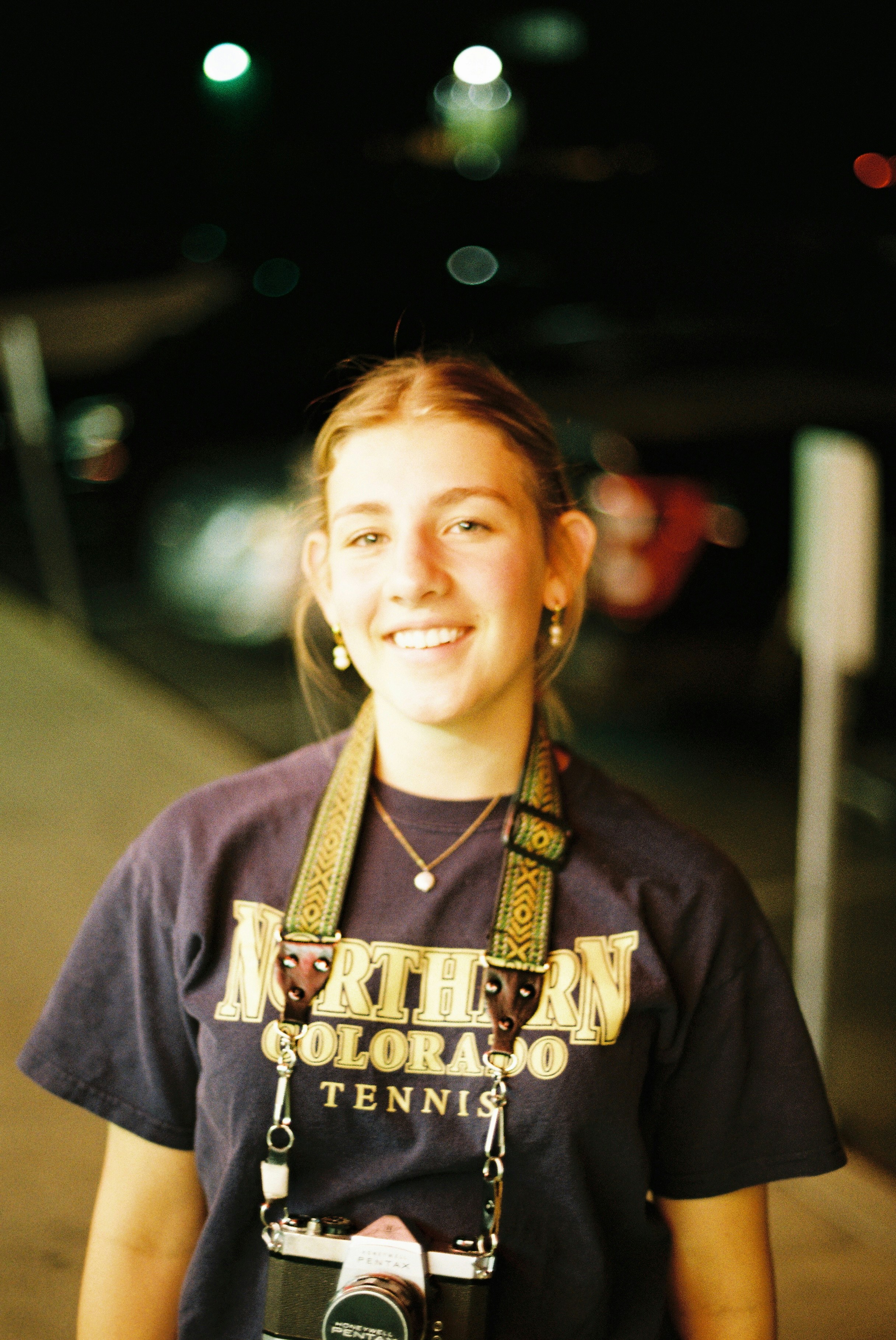 A young woman smiles with a camera around her neck. photo – Free ...